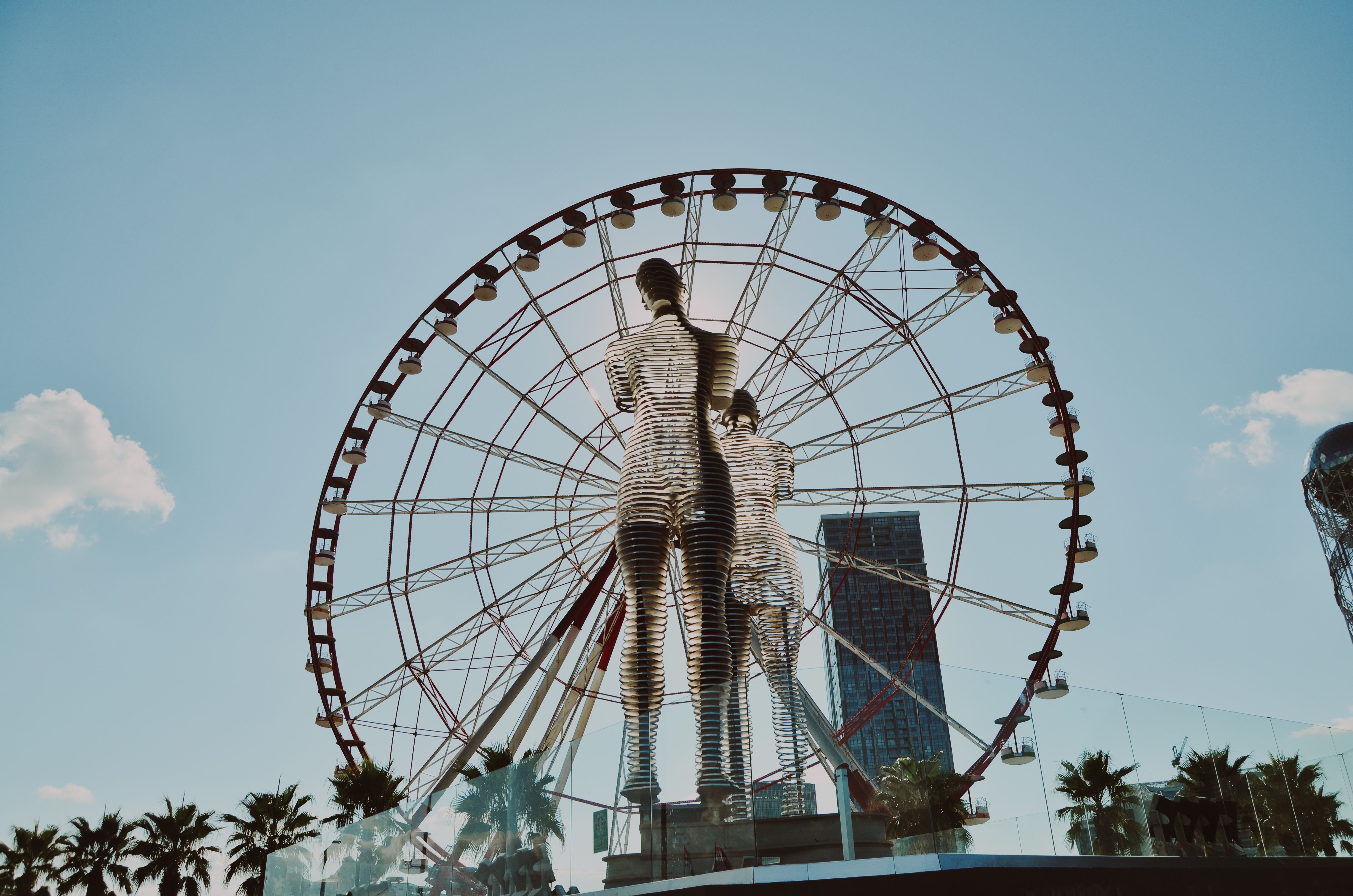 Romantic Sculpture by Ferris Wheel Under Blue Sky · Free Stock Photo