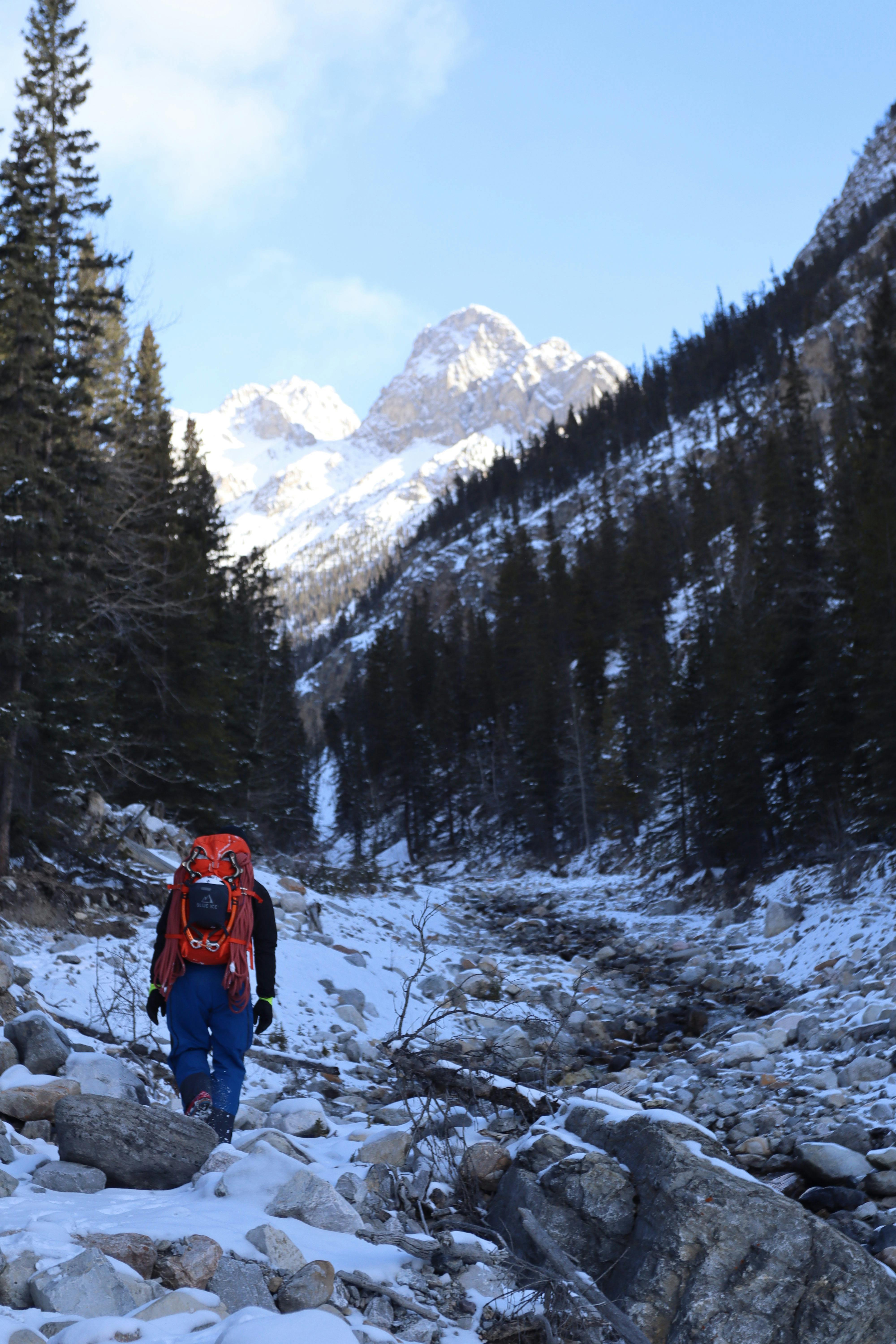 Adventurer Hiking through Snowy Mountain Valley · Free Stock Photo