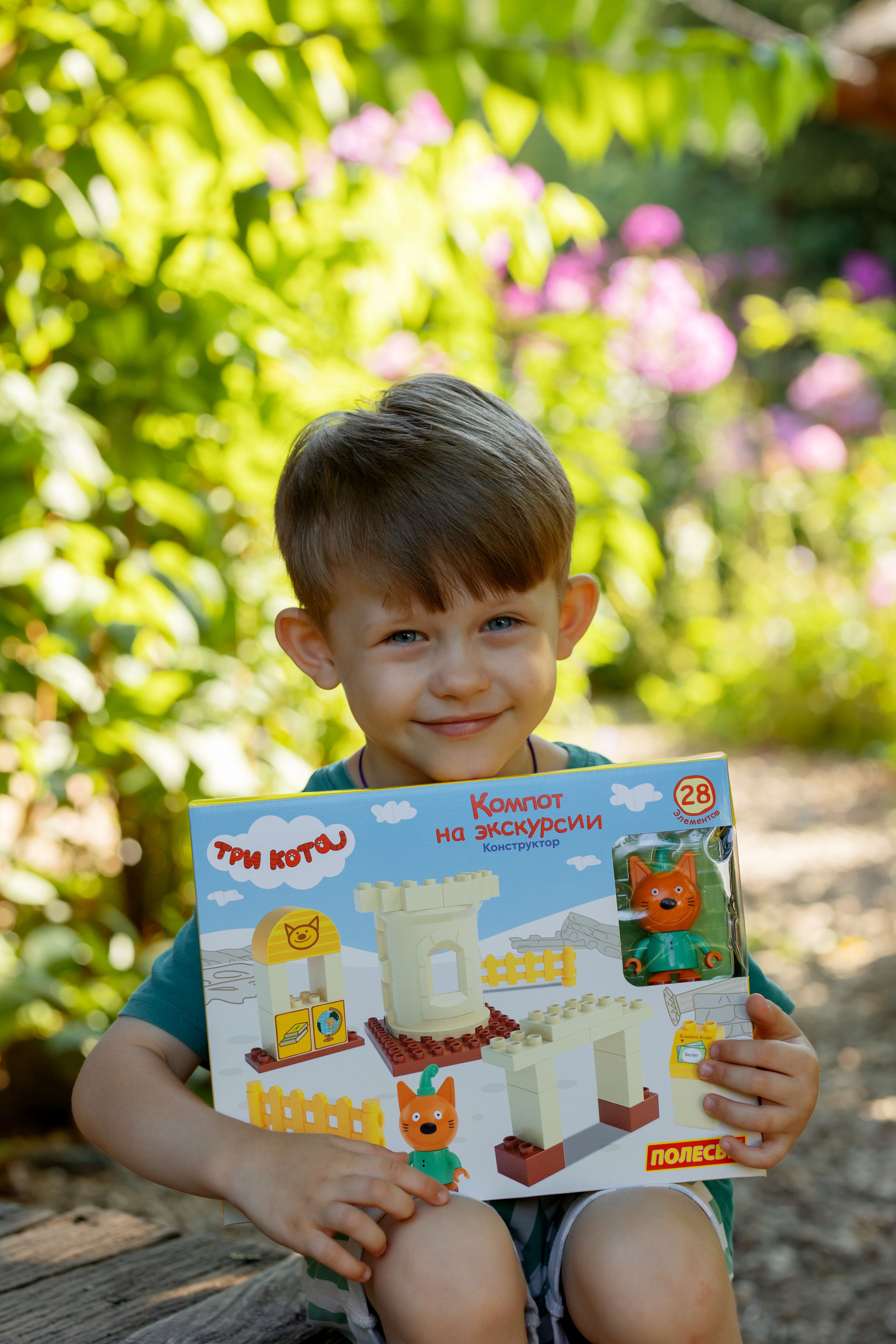 Smiling Boy Holding Toy Box in Sunny Garden · Free Stock Photo