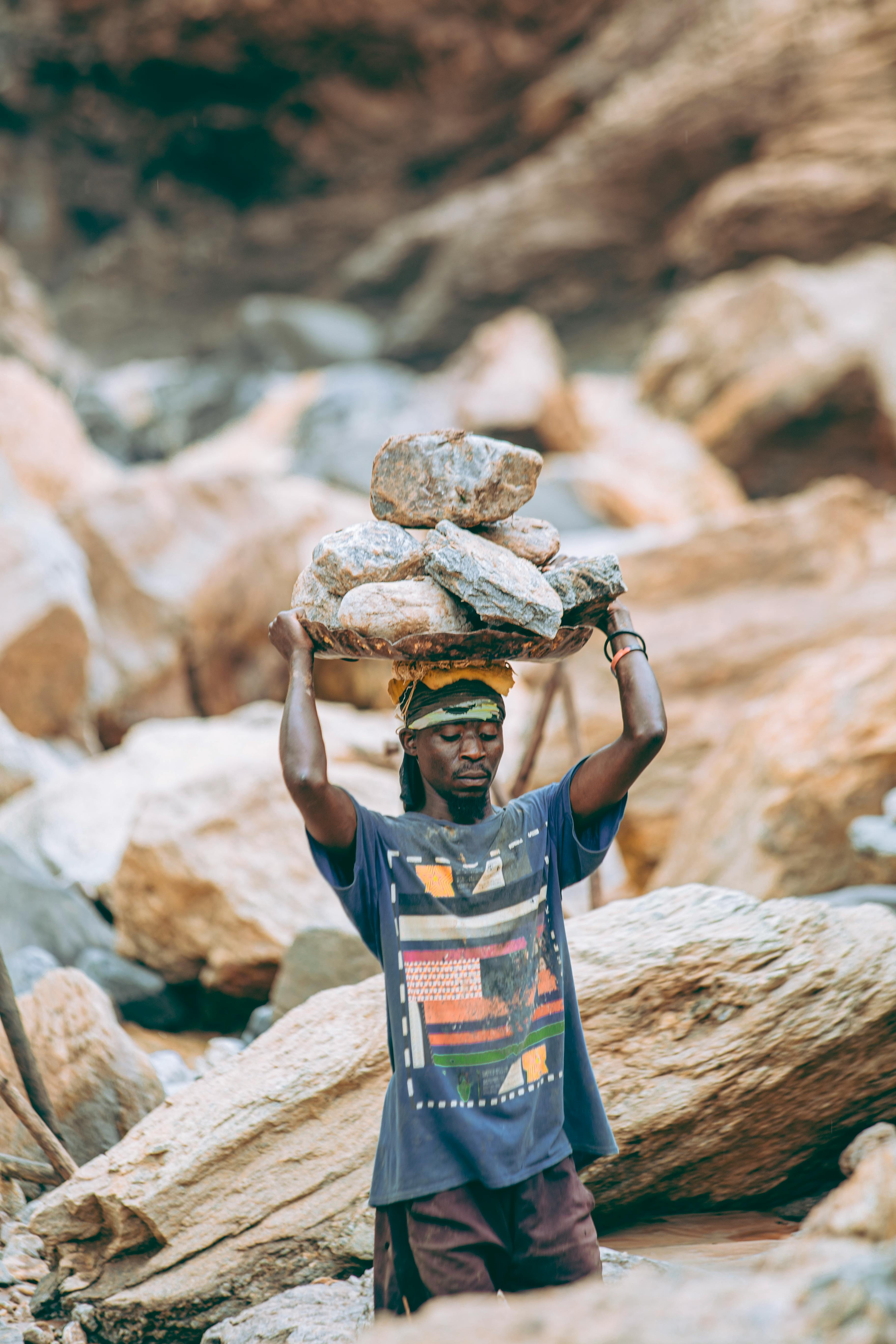 Man Carrying Rocks in a Quarry Setting · Free Stock Photo