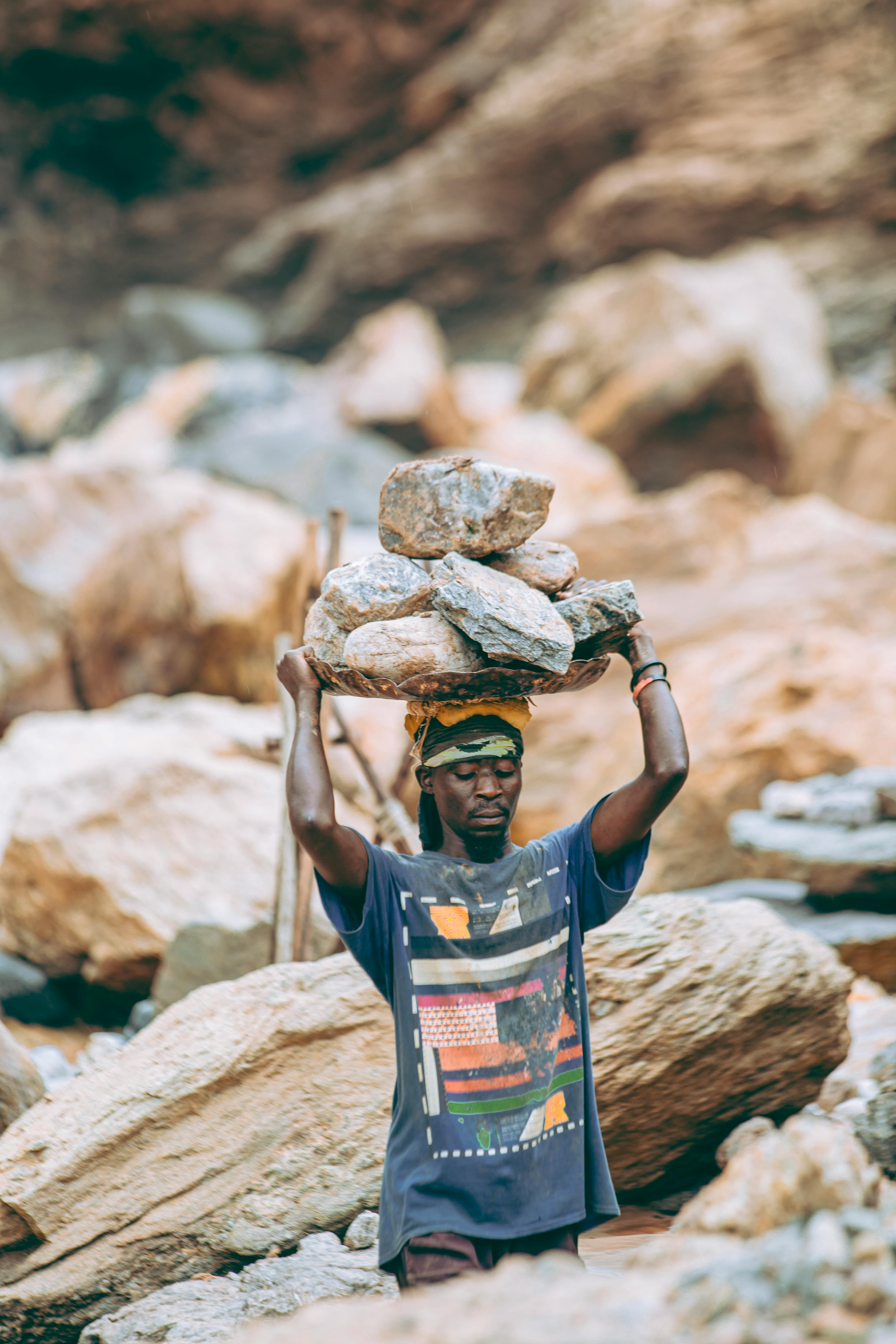 Man Carrying Stones in Rocky Outdoor Setting · Free Stock Photo