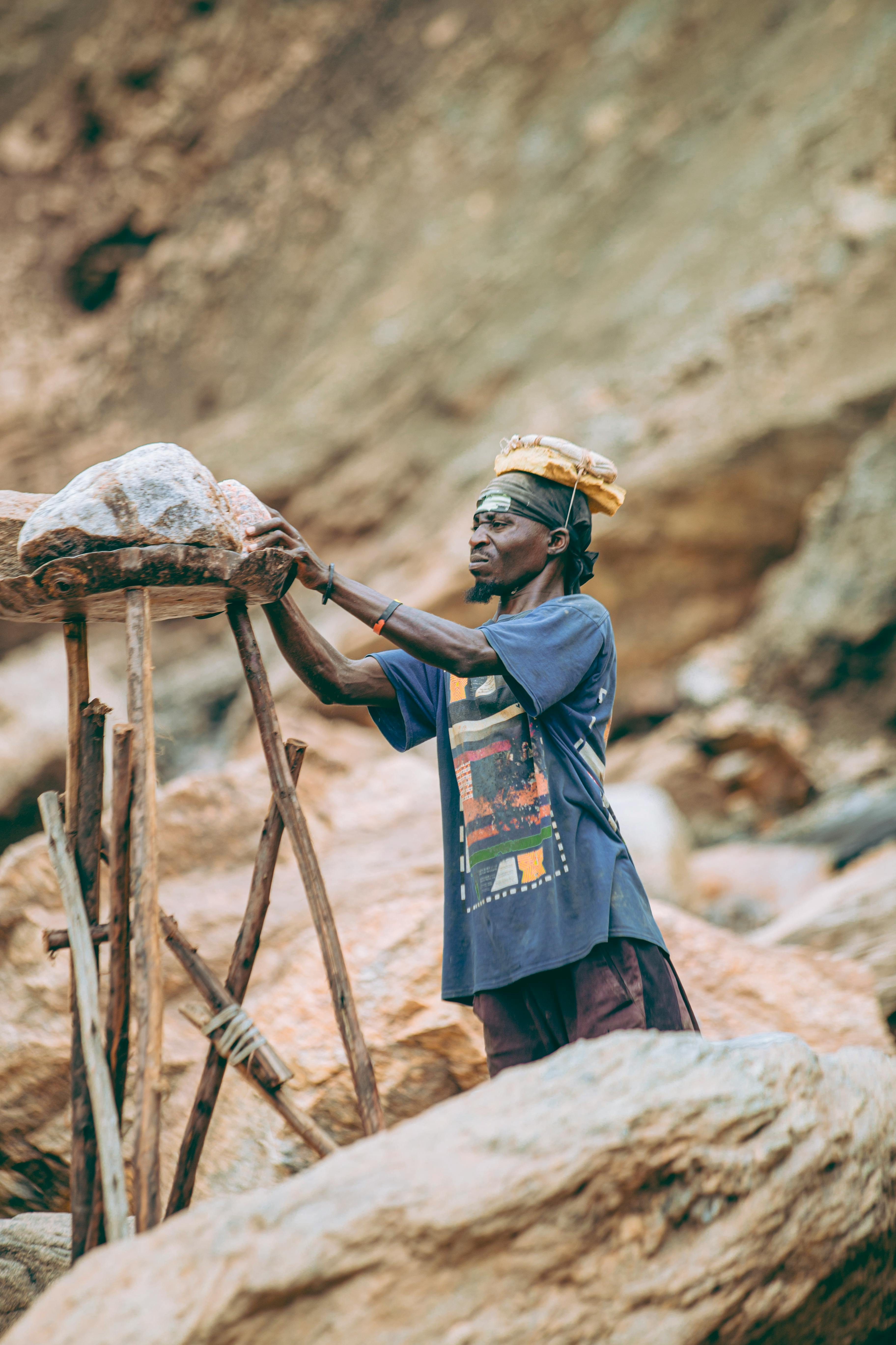 Man Engaging in Traditional Rock Mining Outdoors · Free Stock Photo