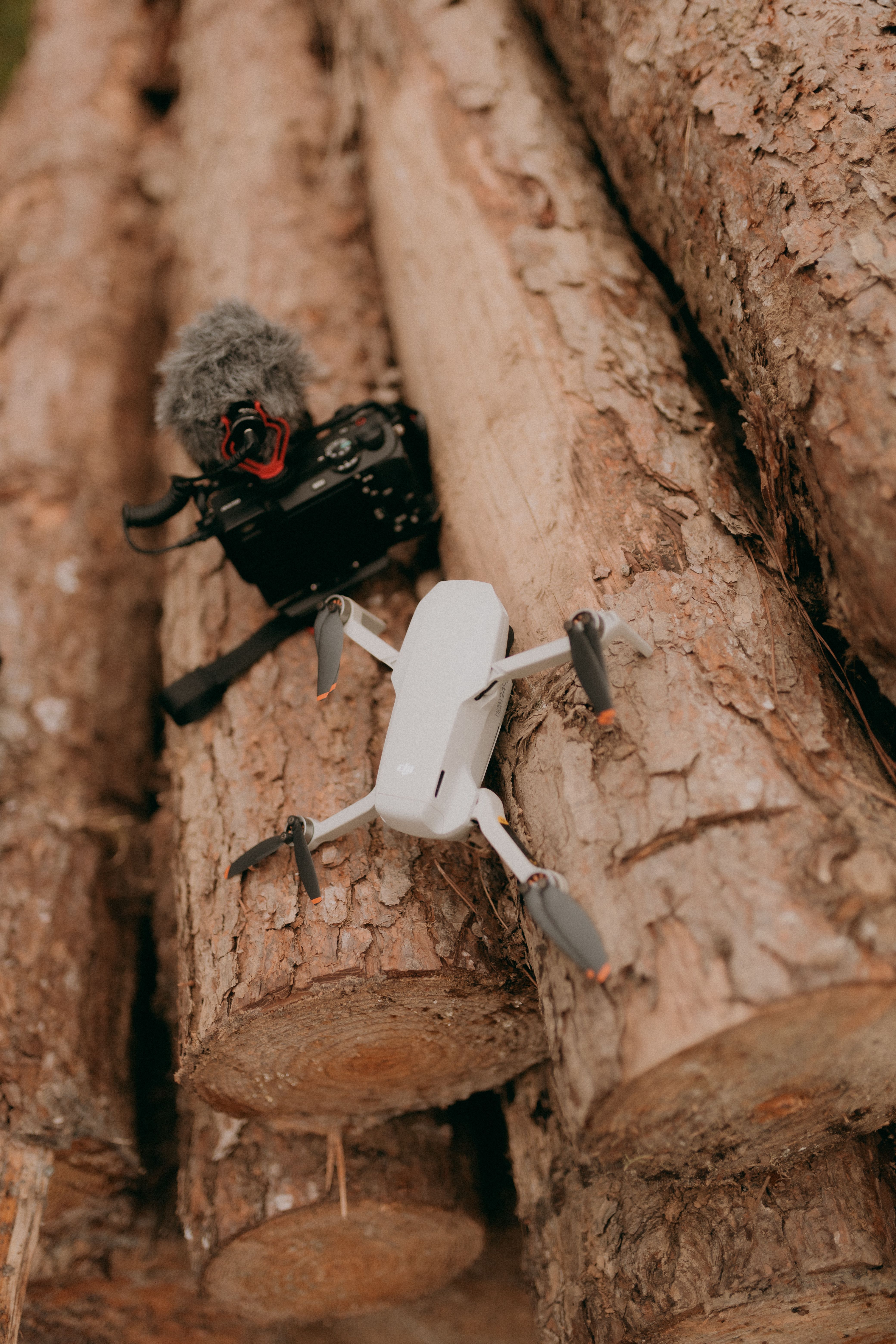 Drone and Camera on Log Stack Outdoors · Free Stock Photo