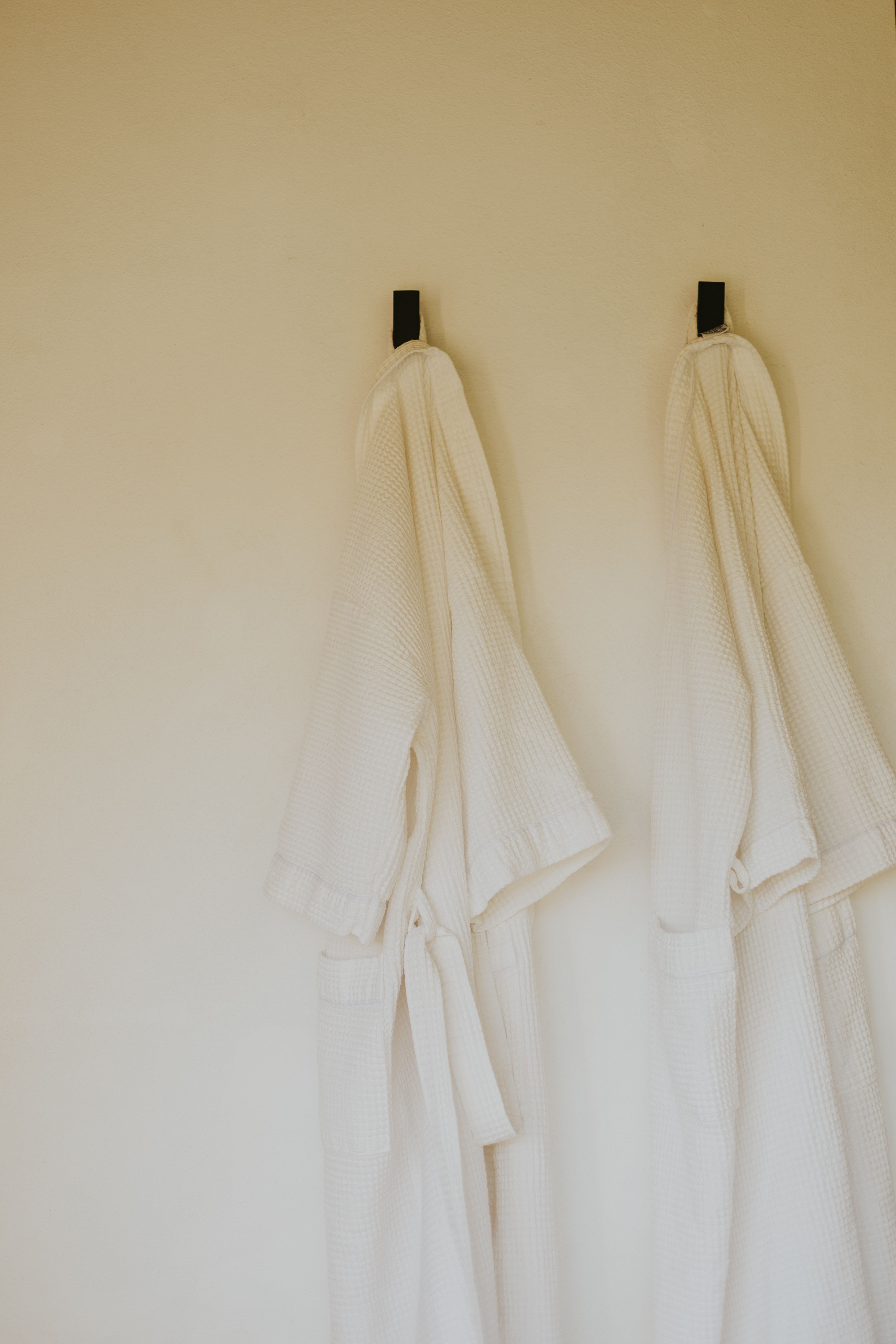 Elegant White Bathrobes Hanging in Minimalist Setting · Free Stock Photo