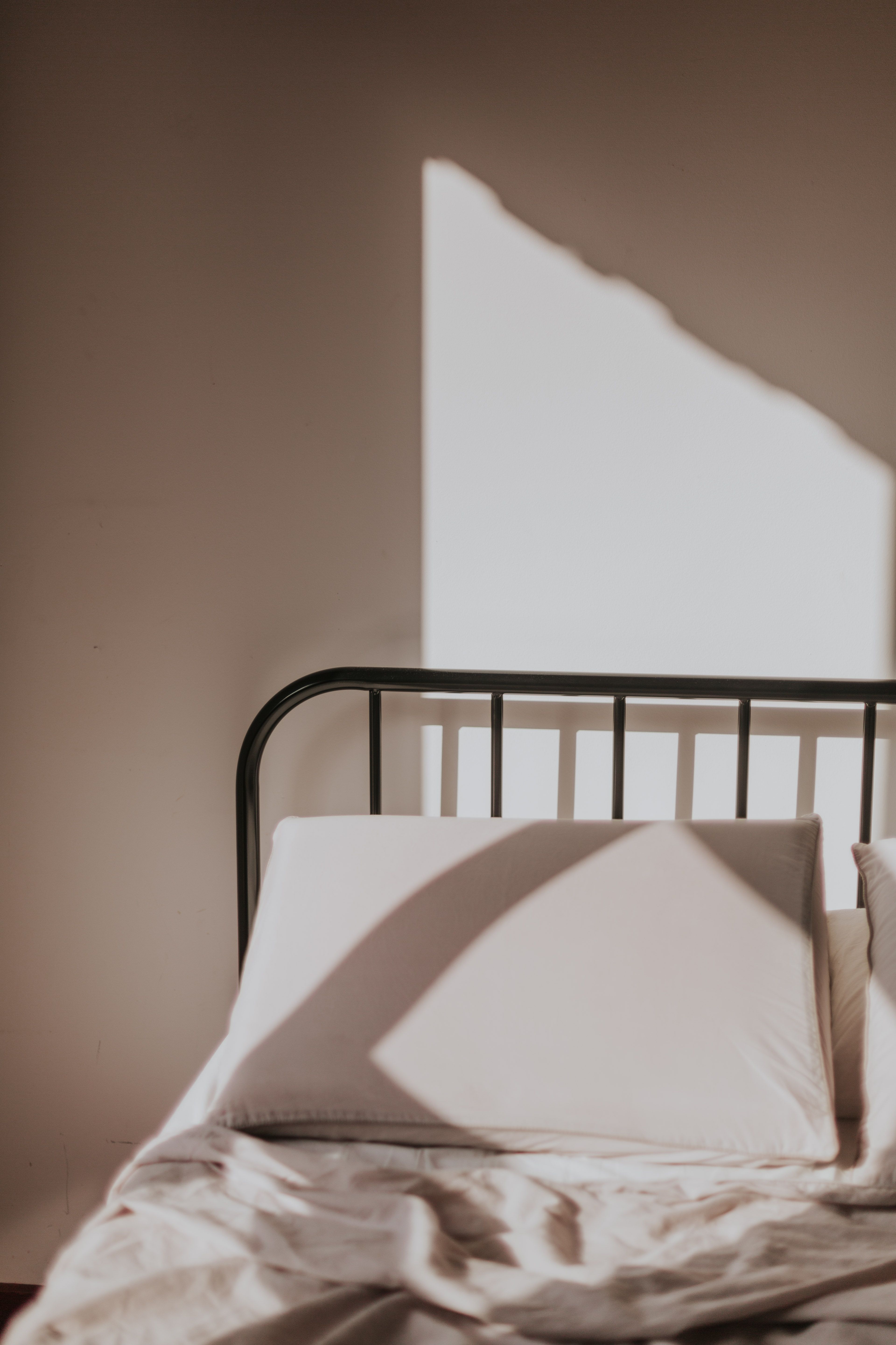 Morning Sunlight Casting Shadows on Minimalist Bed · Free Stock Photo