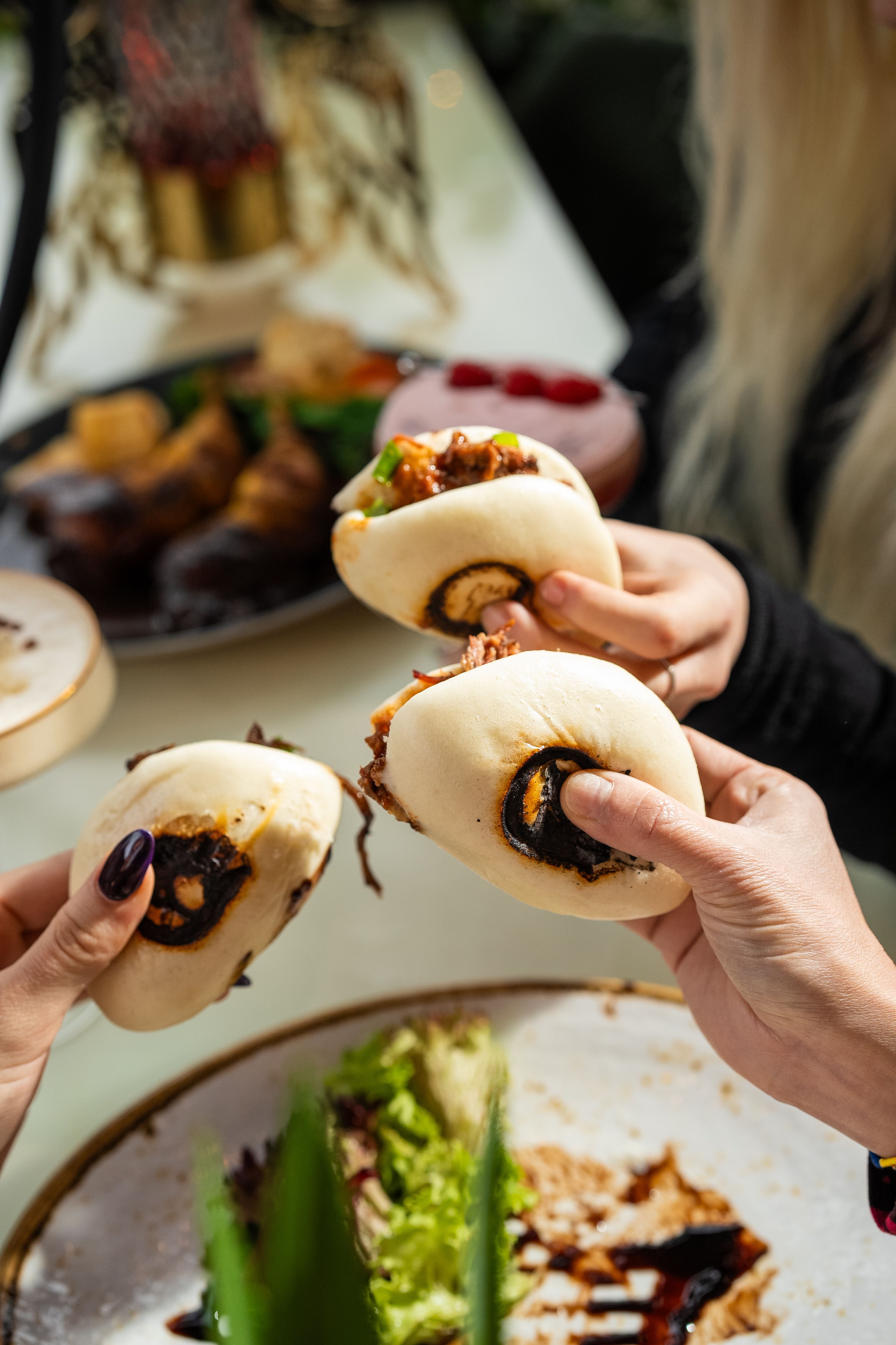 Close-up of Hands Holding Bao Buns at a Dining Table · Free Stock Photo
