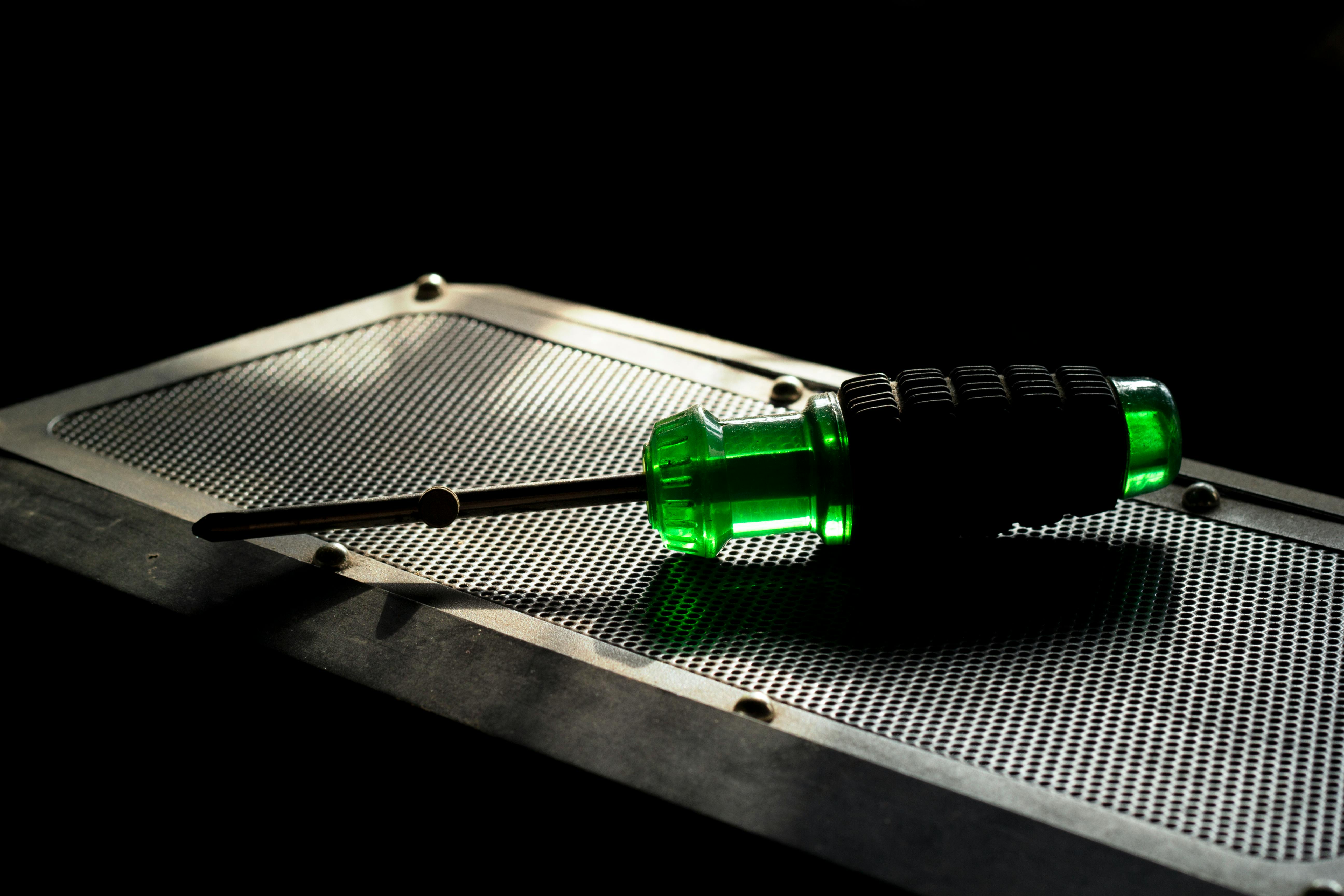 Green Screwdriver on Metallic Surface Close-Up · Free Stock Photo