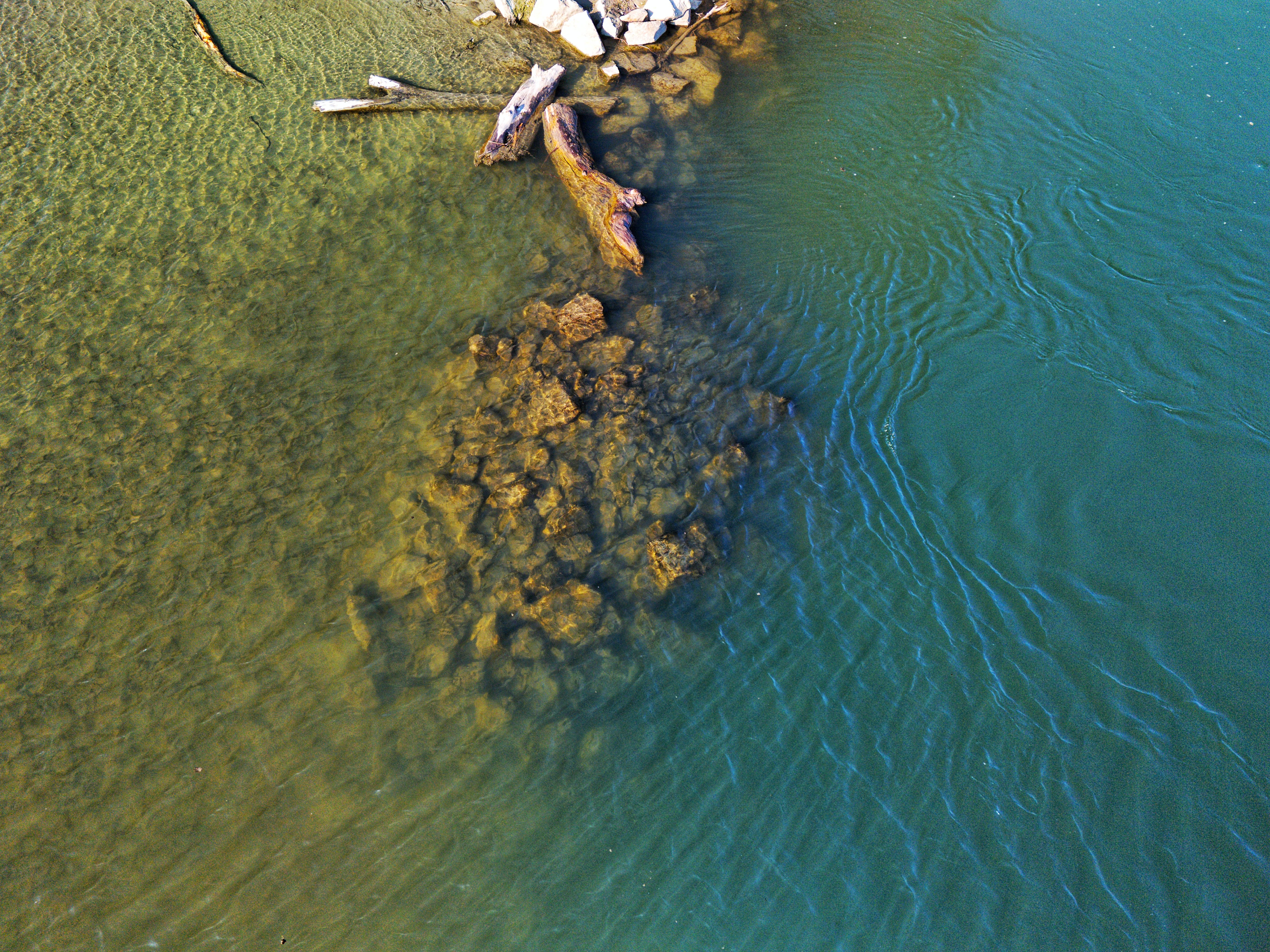 Aerial View of Riverbank with Rocks and Driftwood · Free Stock Photo