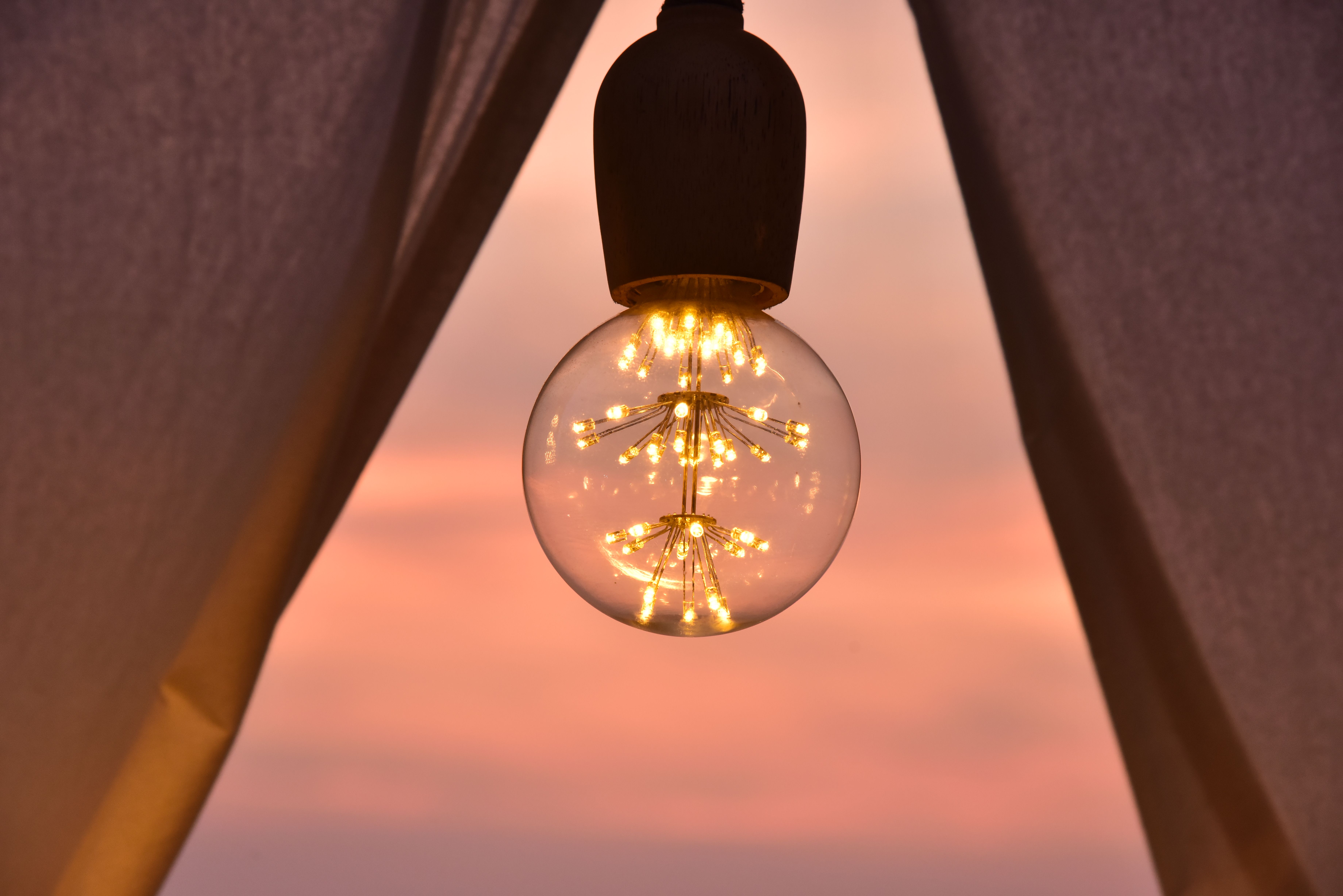 Edison Bulb Glowing at Sunset with Soft Pink Sky · Free Stock Photo