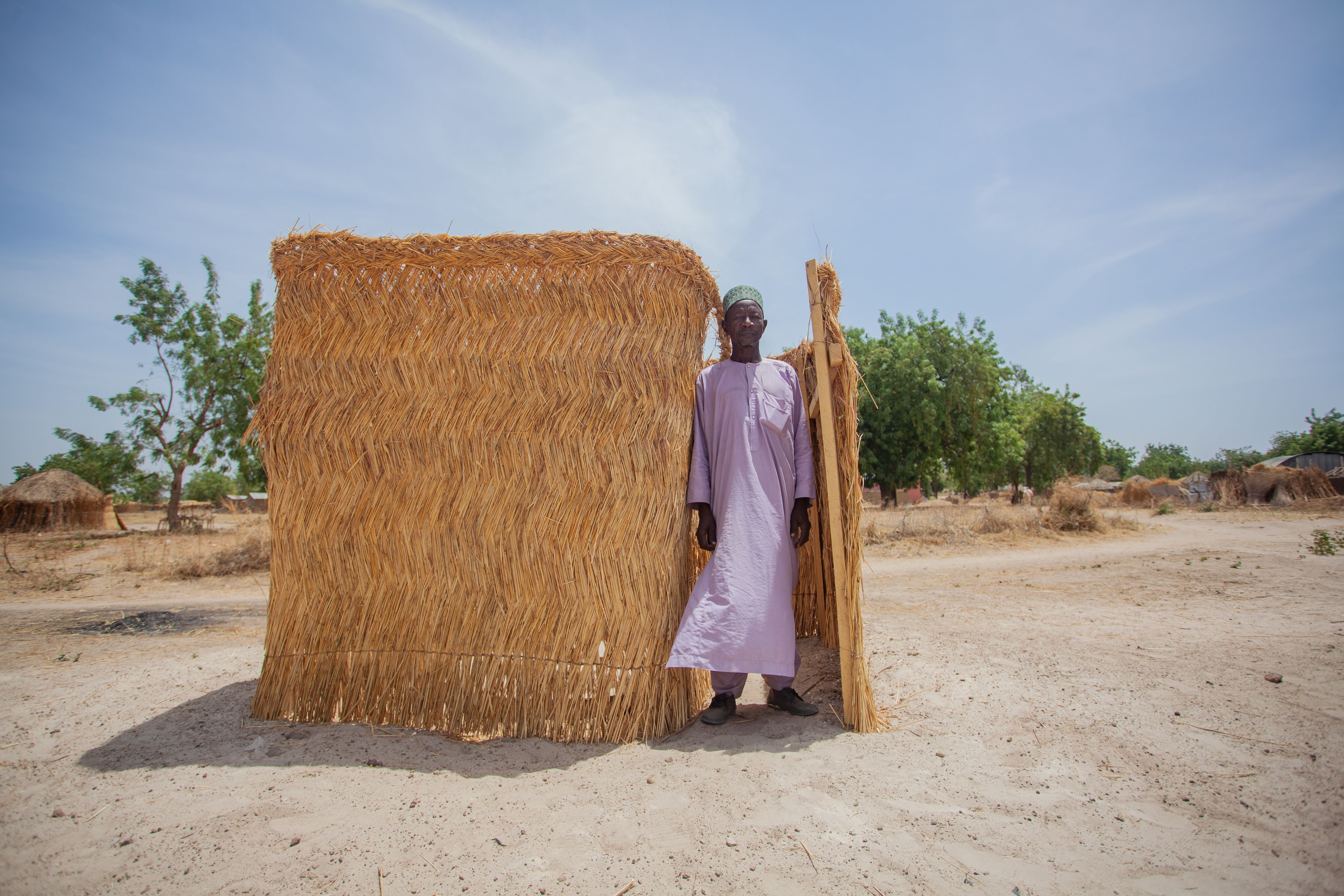 African Man Standing by Straw Structure in Desert · Free Stock Photo