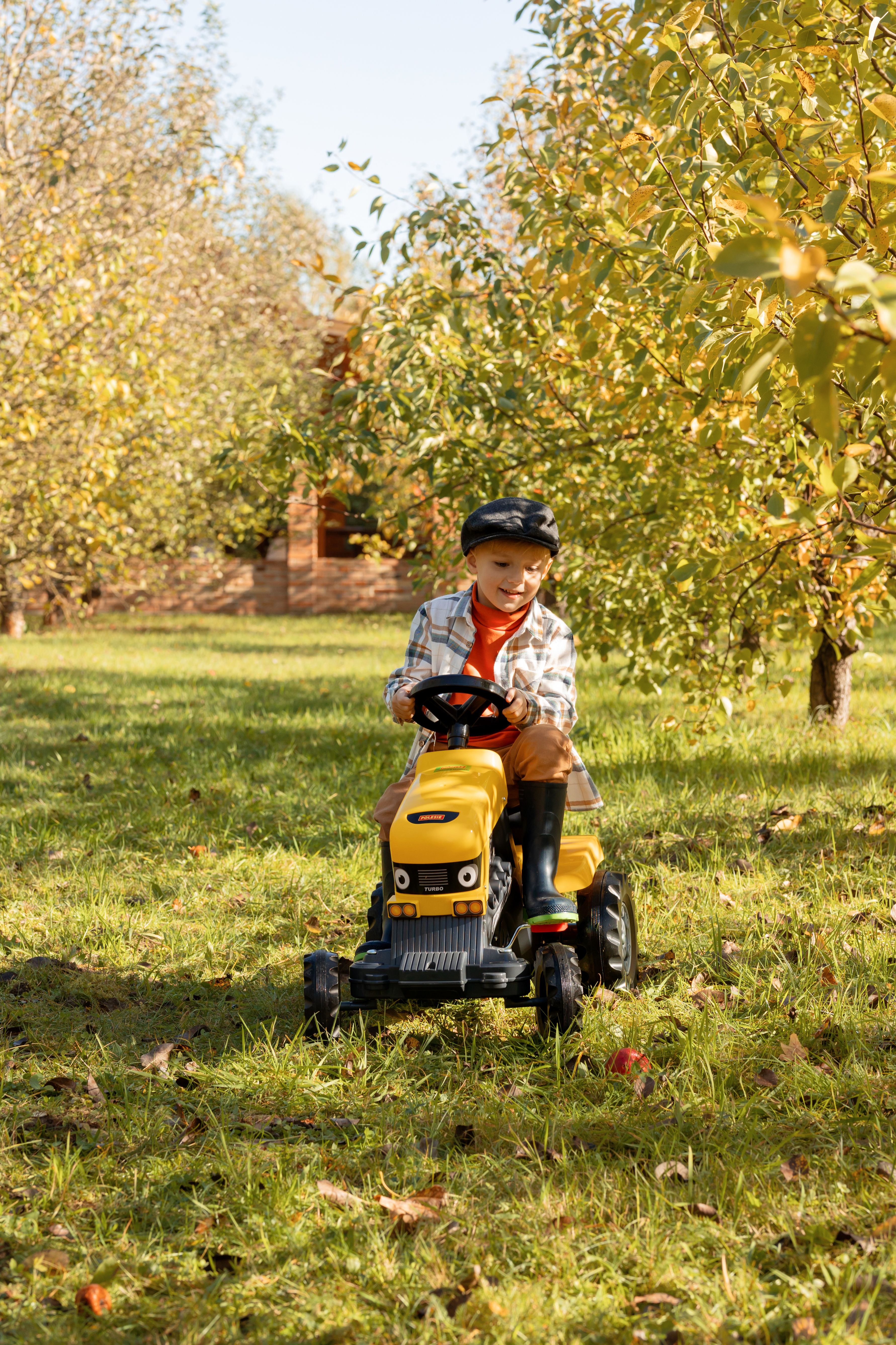 Child Enjoying a Ride on Toy Tractor in Autumn Orchard · Free Stock Photo