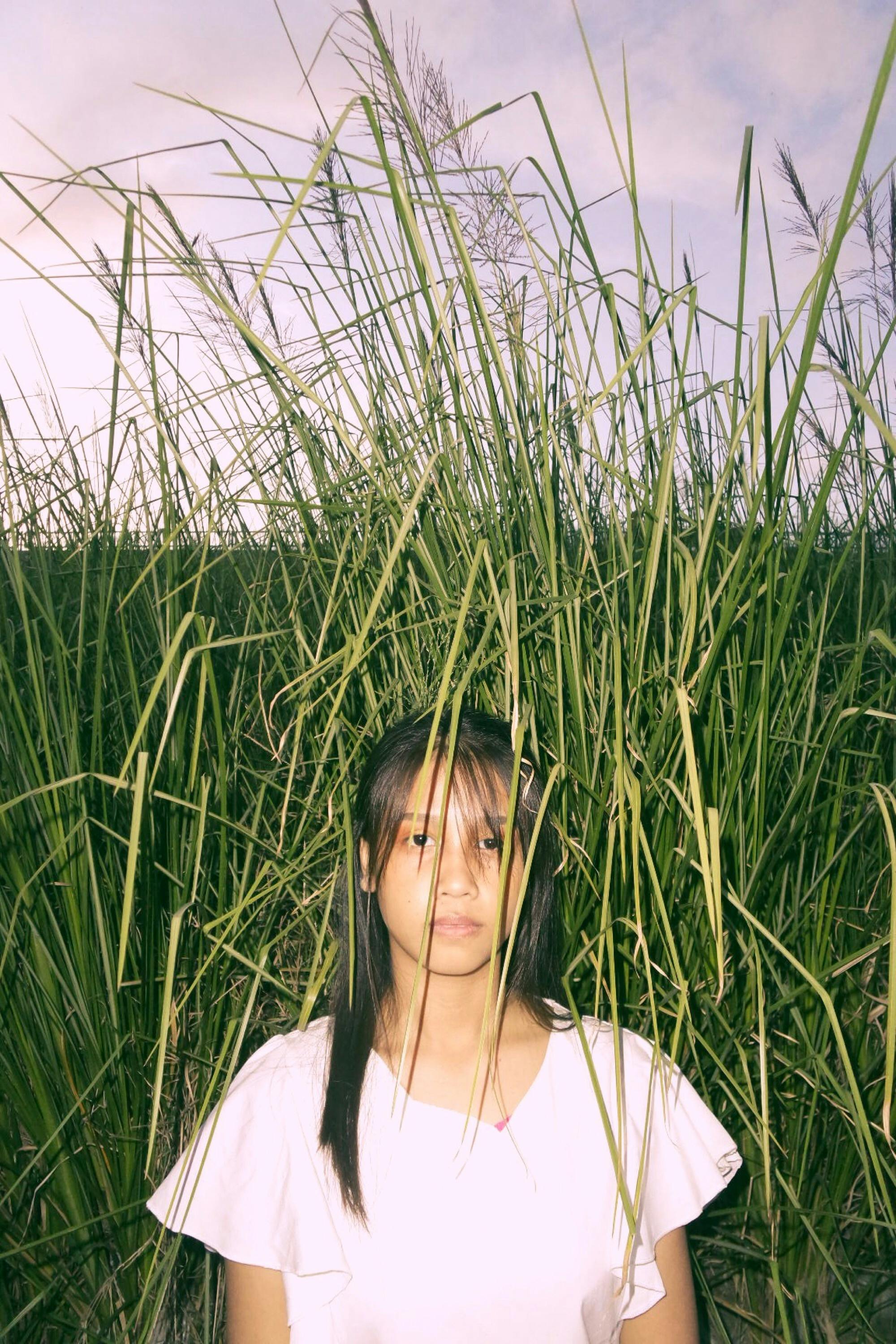 Ethnic teenager in overgrown grass in field under cloudy sky · Free ...