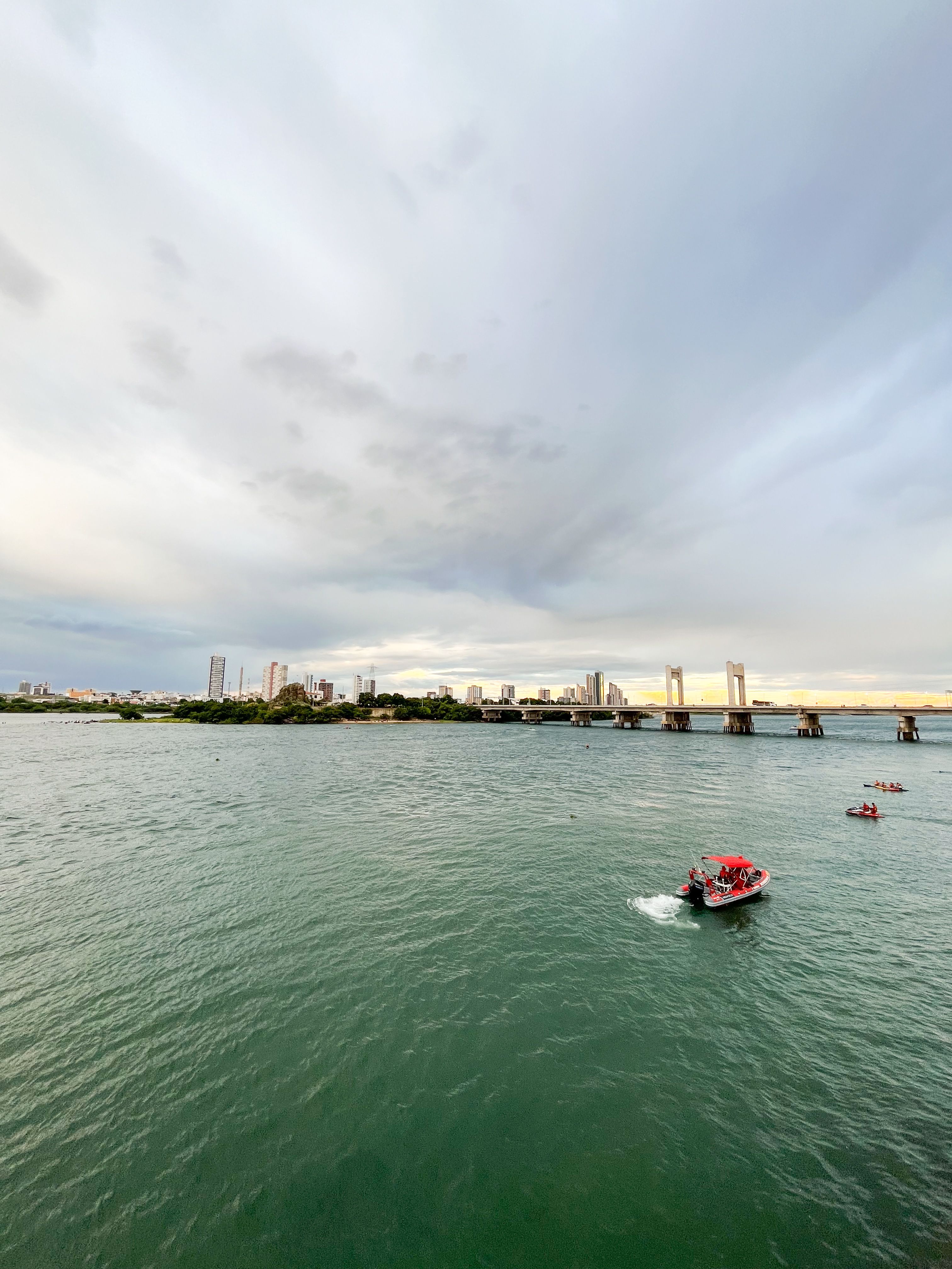 River with Bridge and Boat Under Dramatic Sky · Free Stock Photo