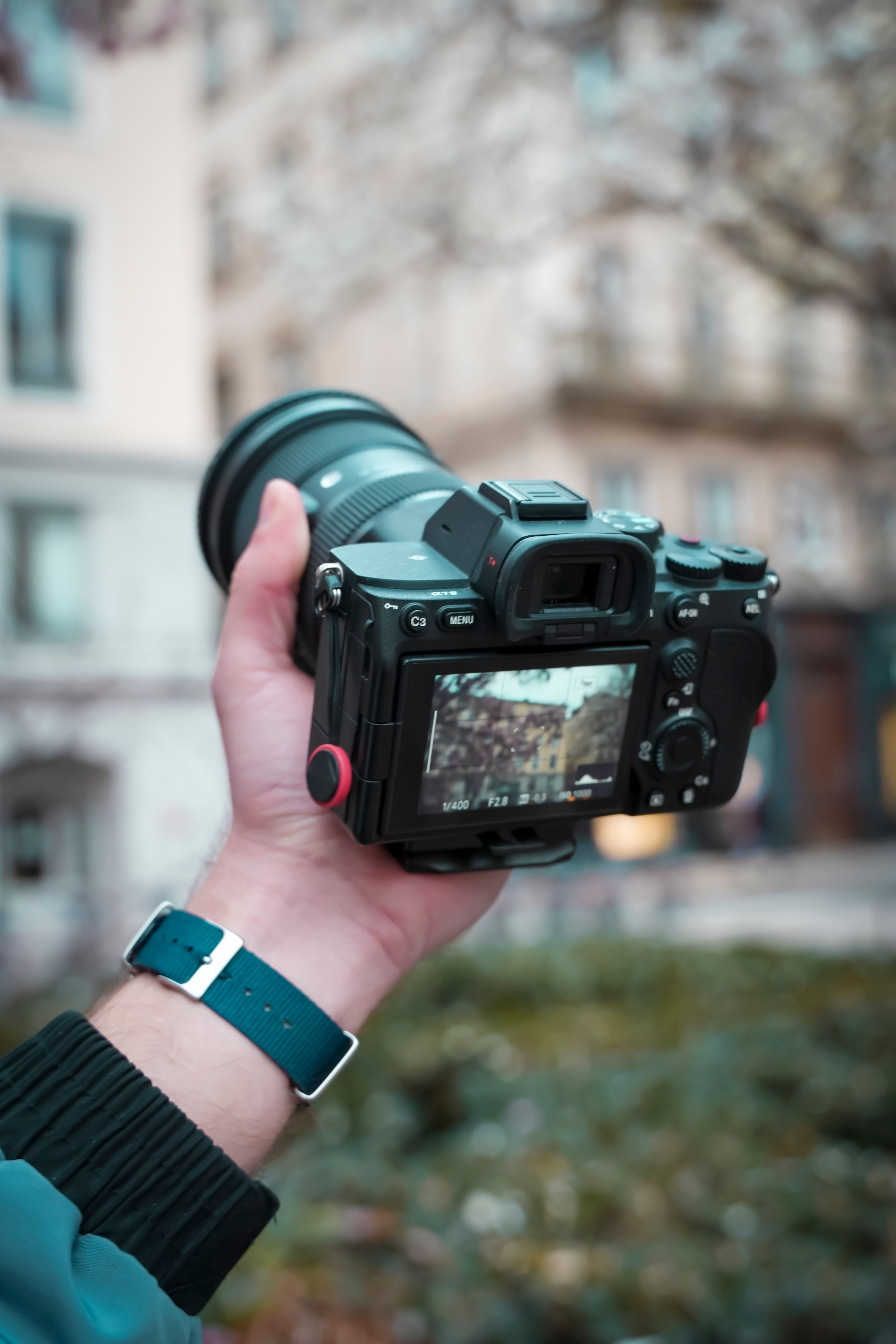 Professional Photographer Holding Camera Outdoors · Free Stock Photo