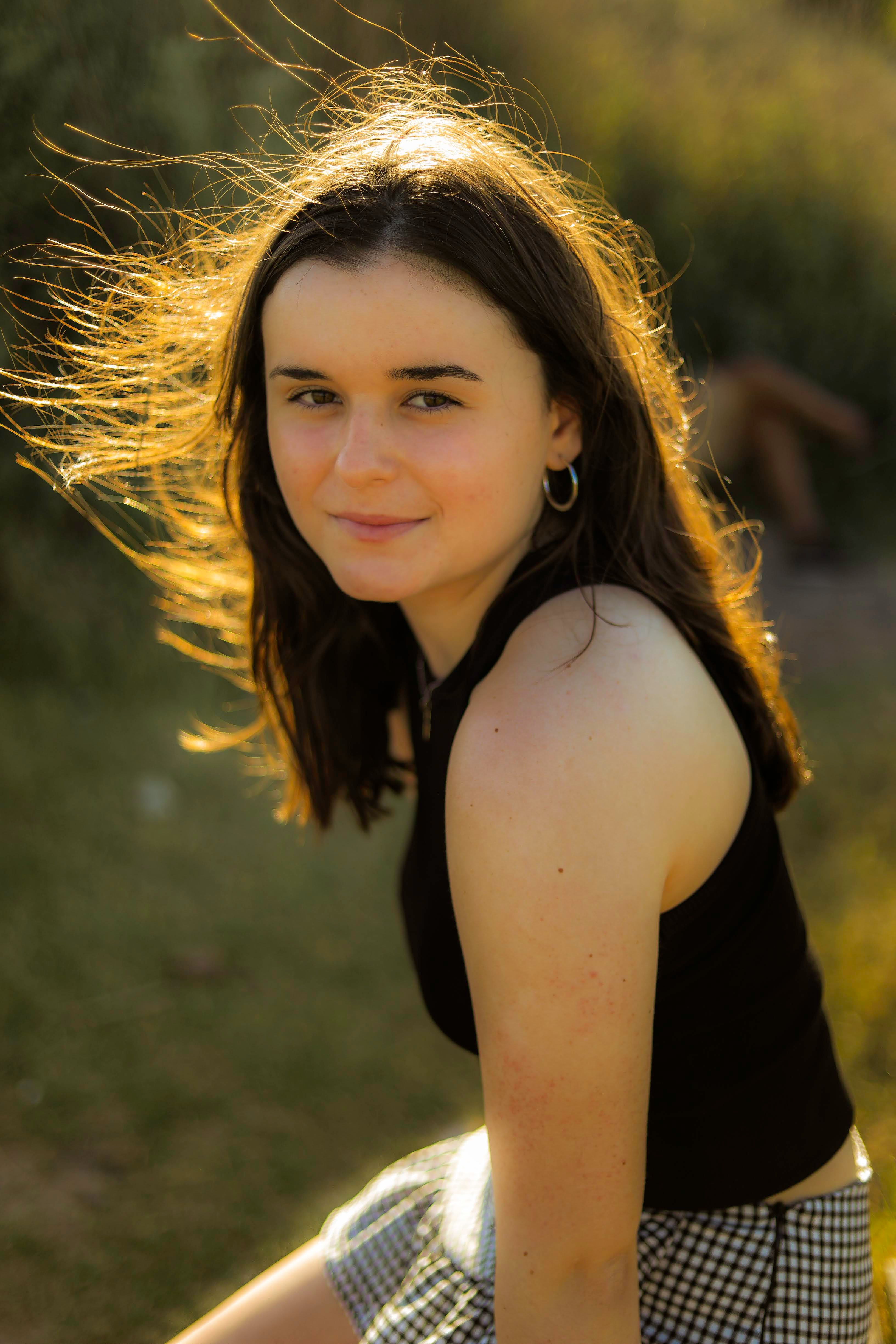 Sunlit Portrait of Smiling Young Woman Outdoors · Free Stock Photo