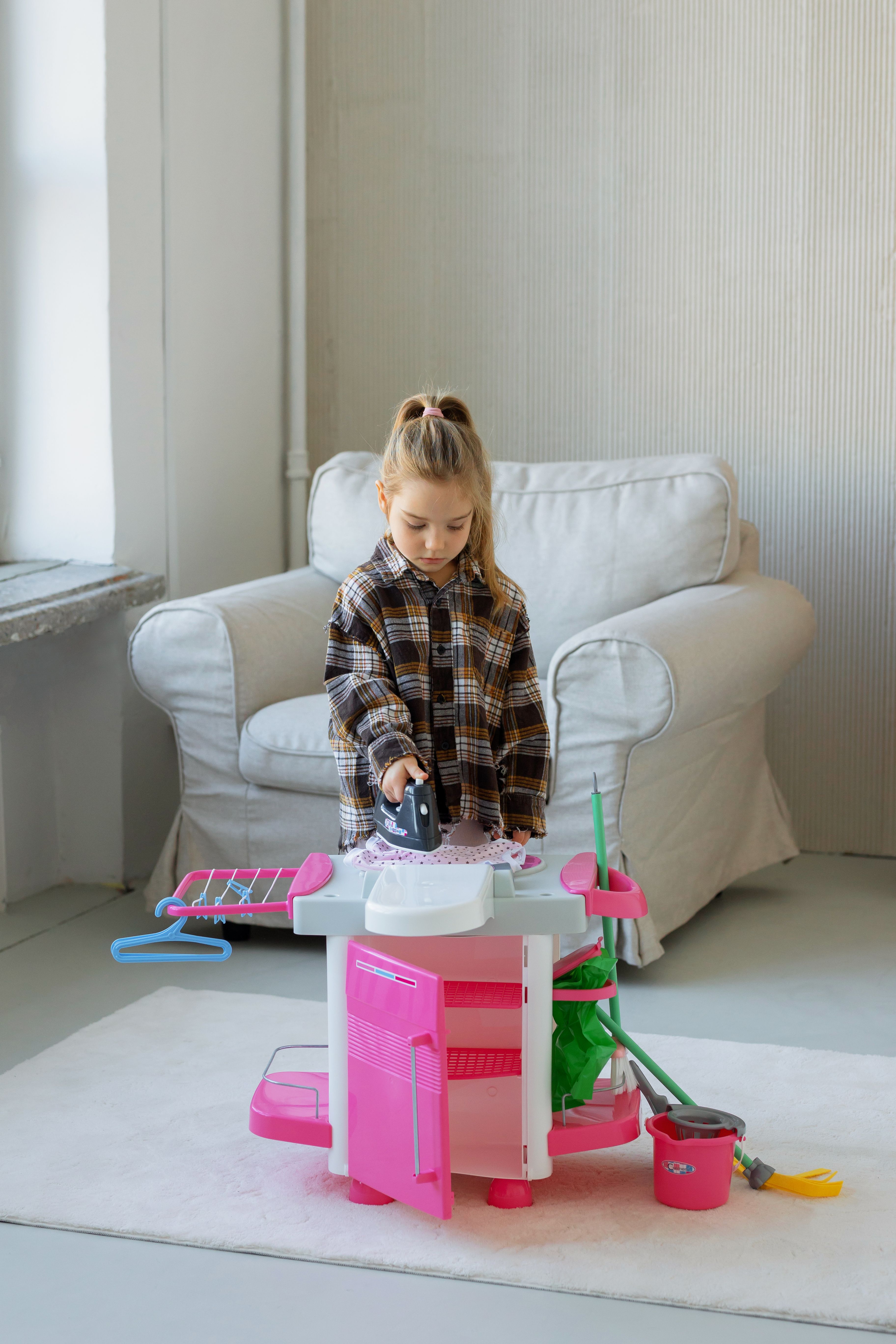 Young Girl Playing with a Toy Ironing Set Indoors · Free Stock Photo