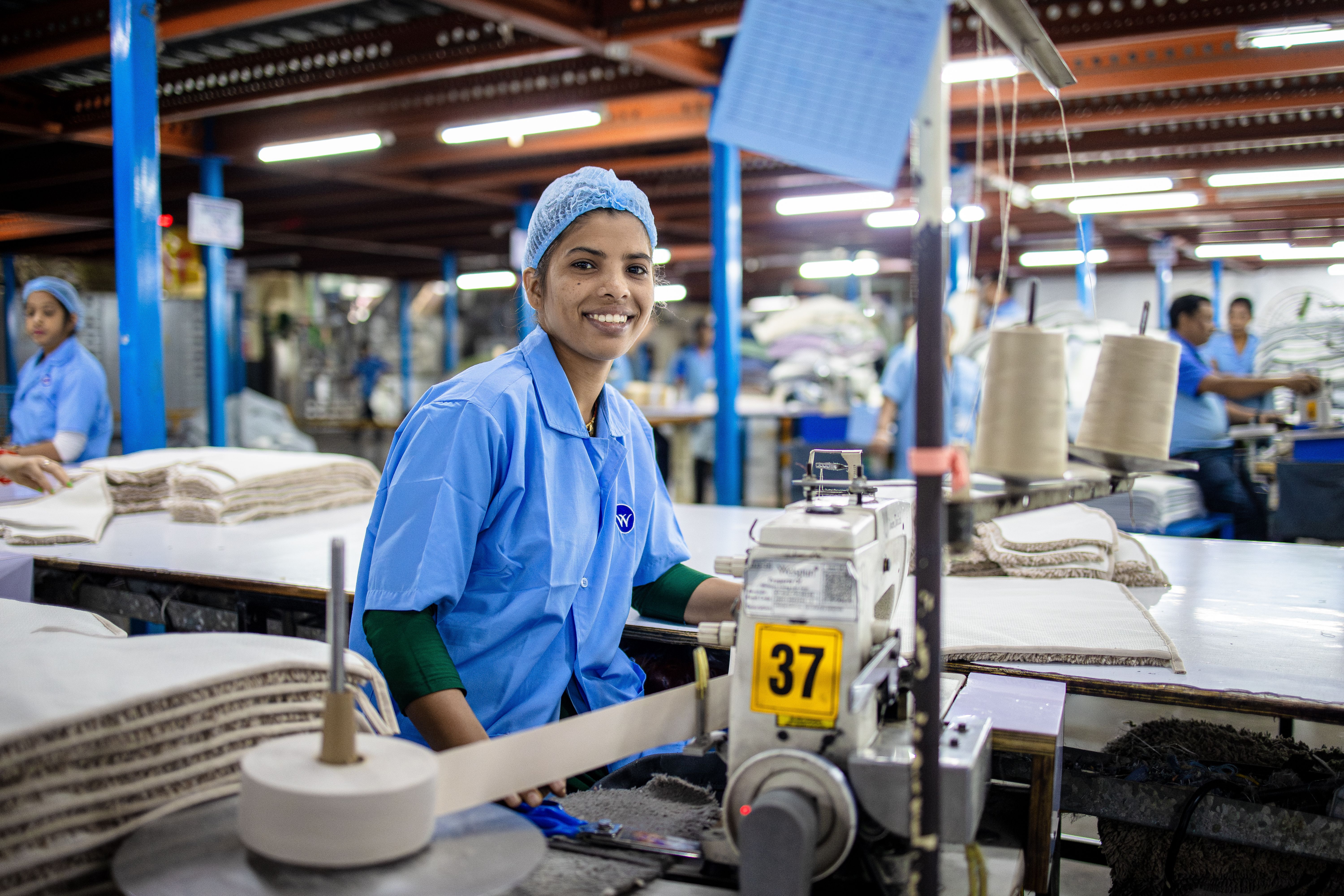 Smiling Textile Worker in Modern Factory Setting · Free Stock Photo