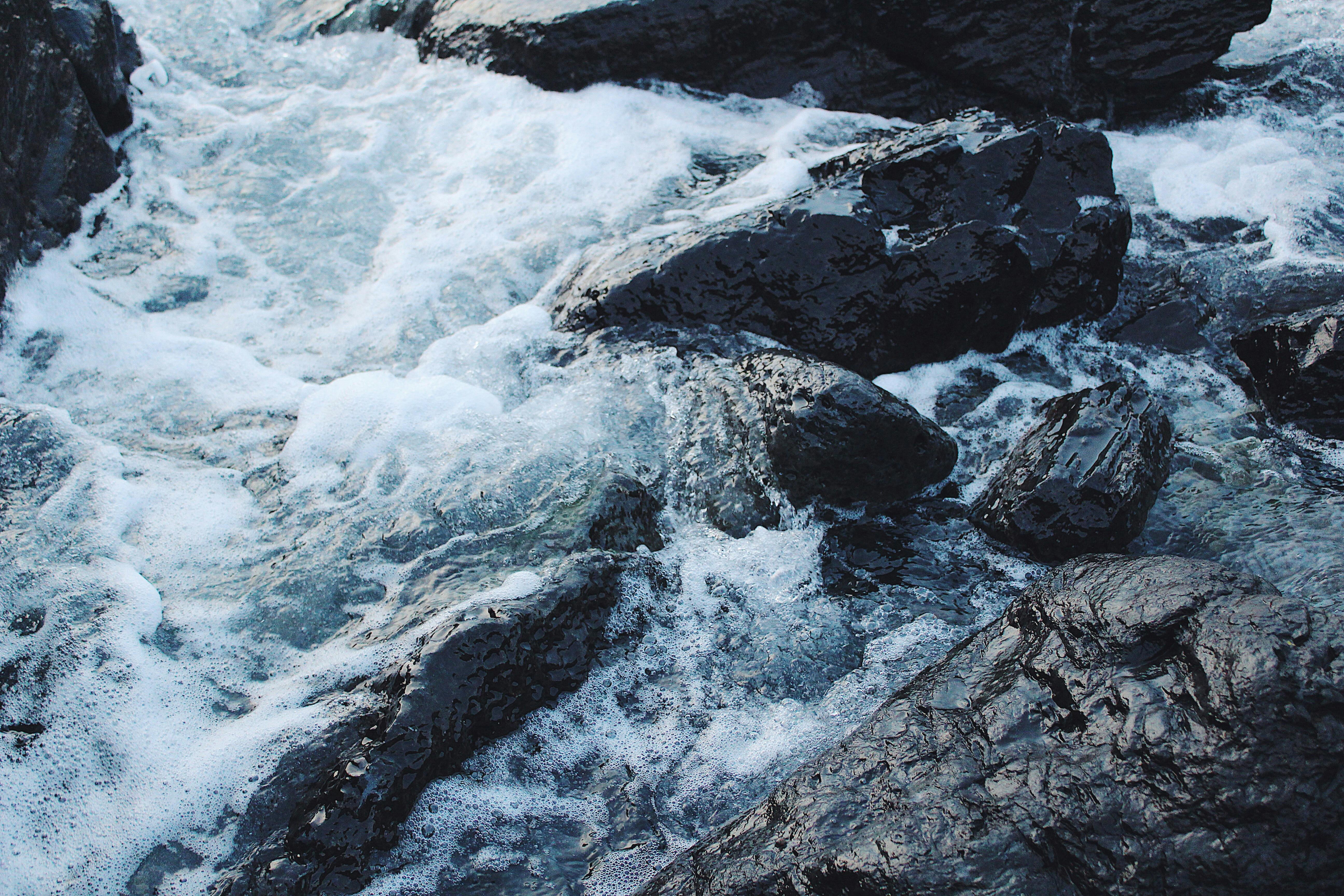 High Angle Photo of Body of Water Splashing Against Gray Rocks · Free ...
