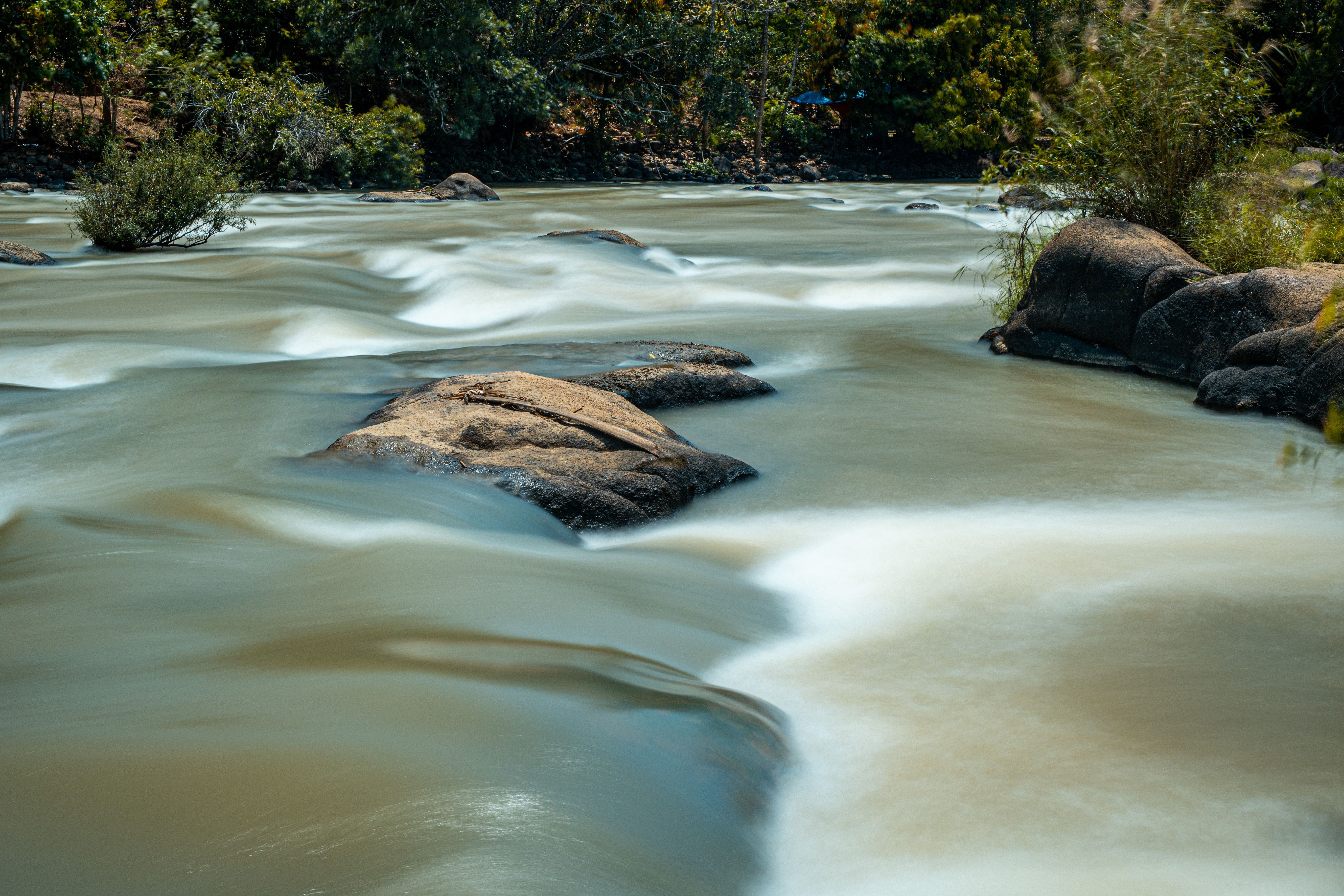 Serene River Flowing Through Rocks in Nature · Free Stock Photo