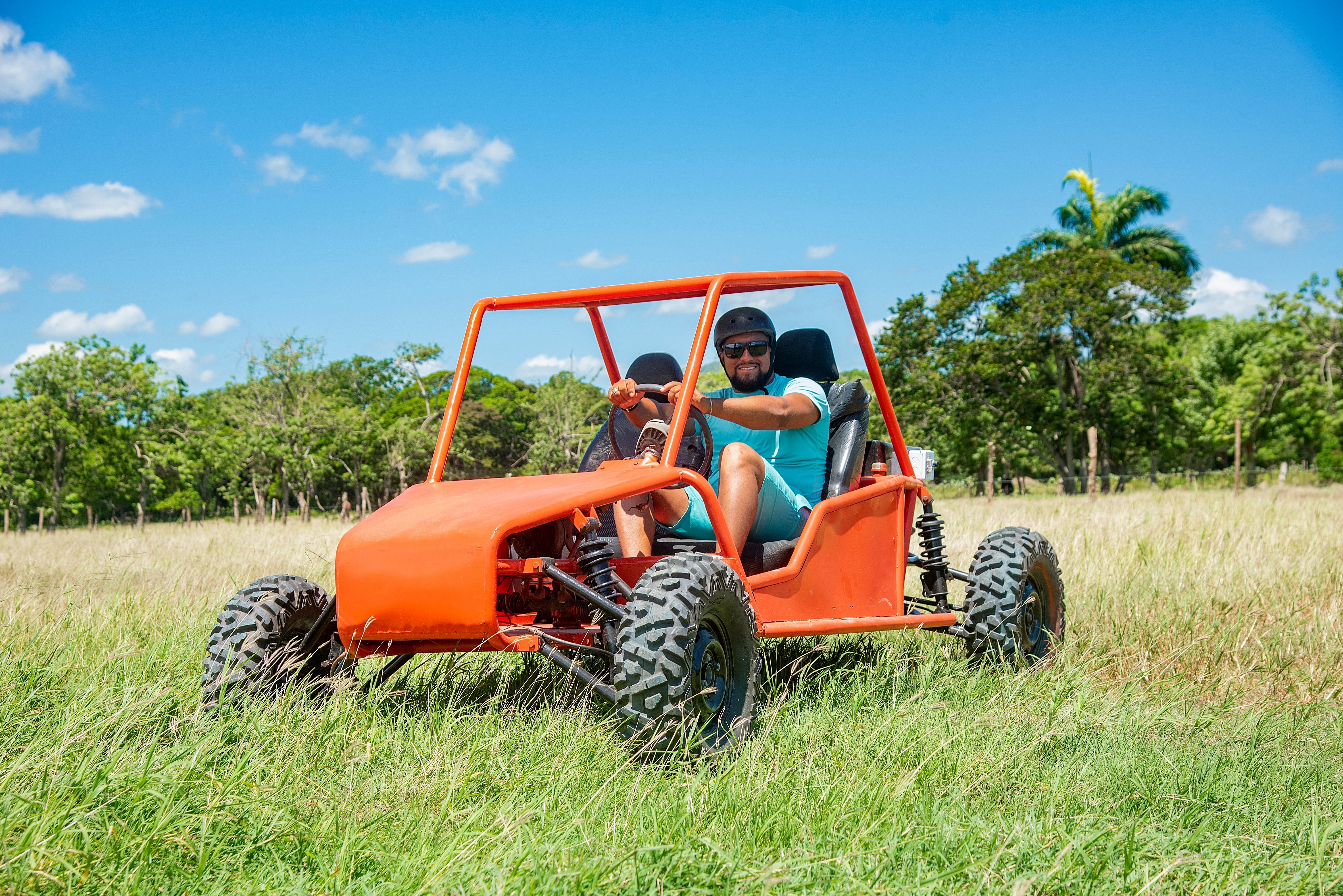 Man driving an orange dune buggy in open field · Free Stock Photo
