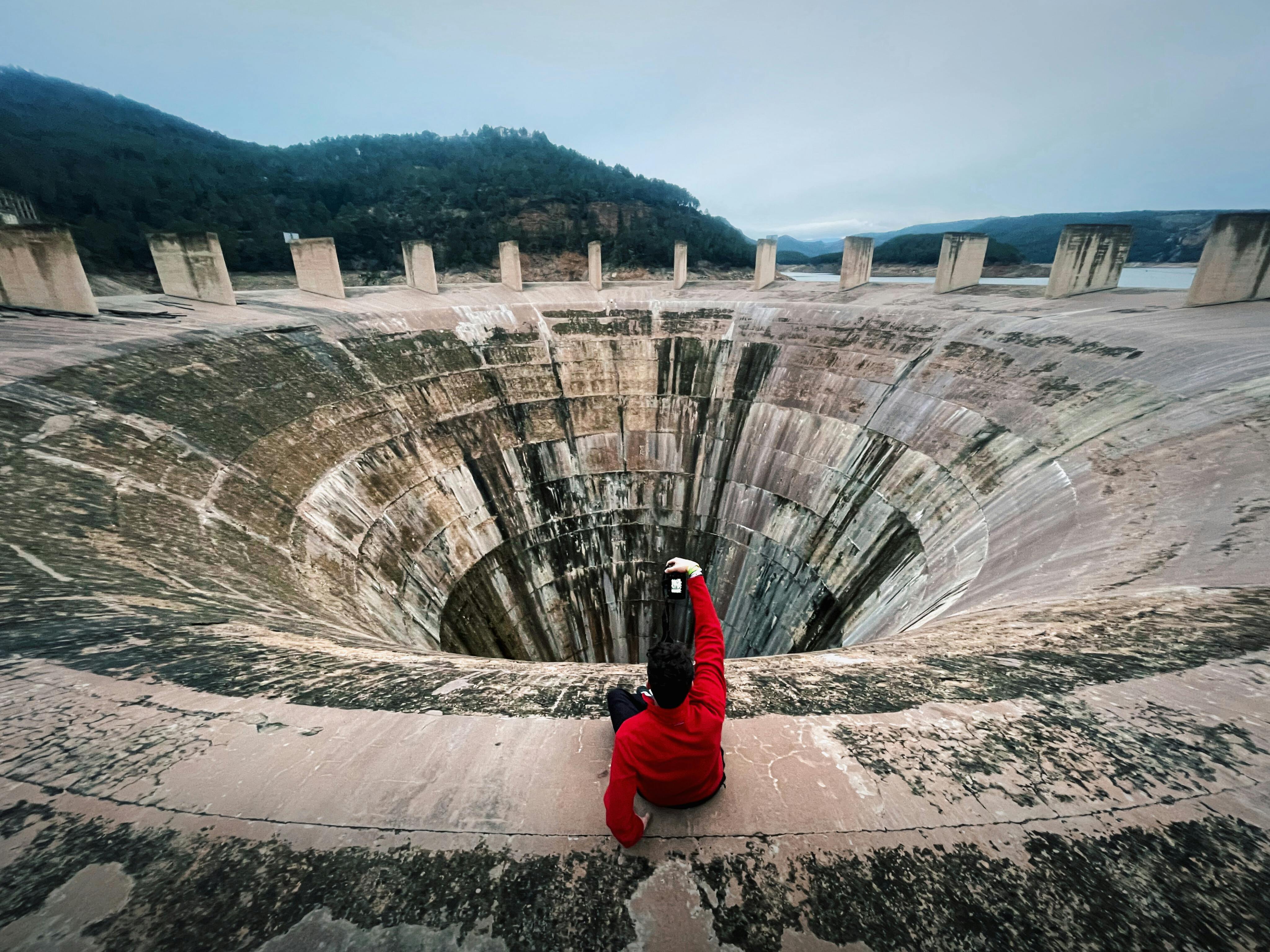 Person Photographing Massive Dam Spillway Outdoors · Free Stock Photo