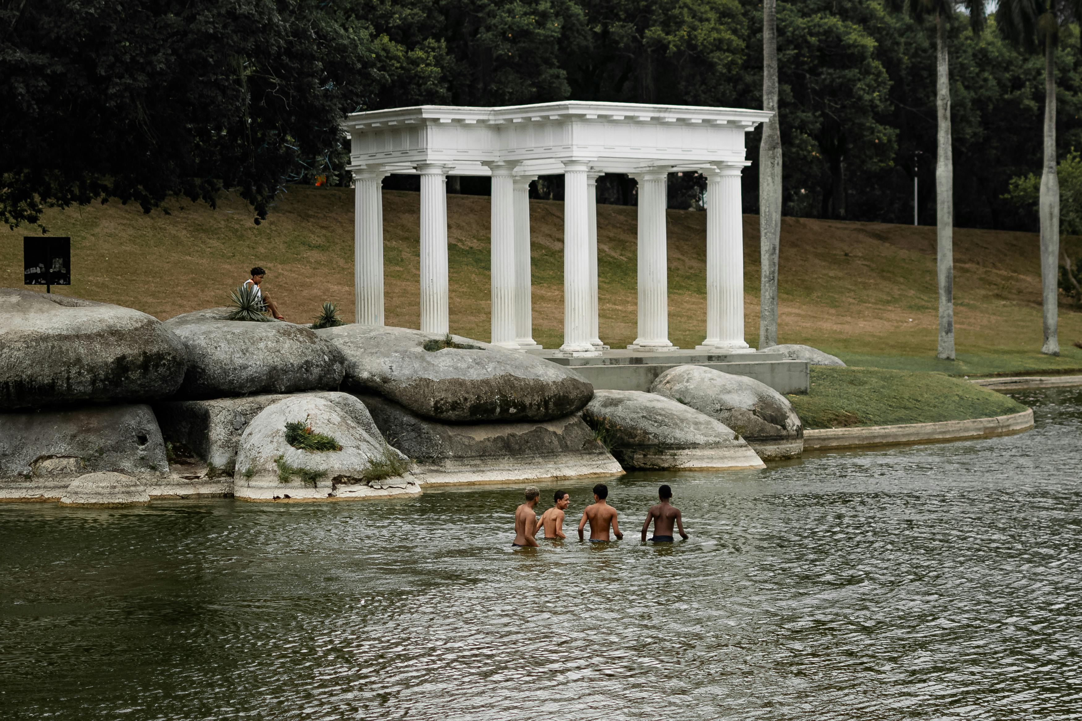 Serene Scene of Boys Swimming by Ancient Columns · Free Stock Photo
