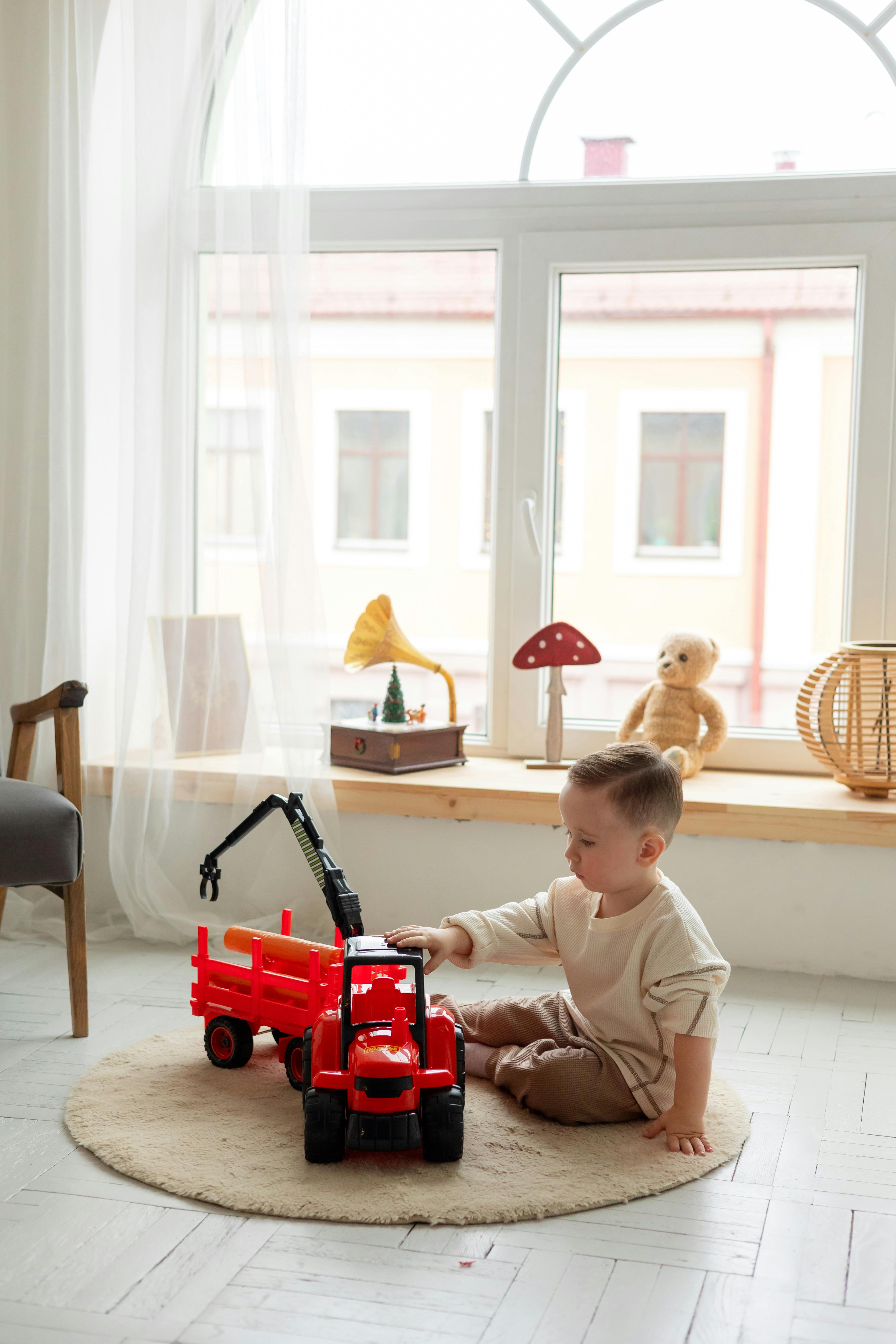 Niño Jugando Con Un Tractor De Juguete Rojo En El Interior · Foto de ...