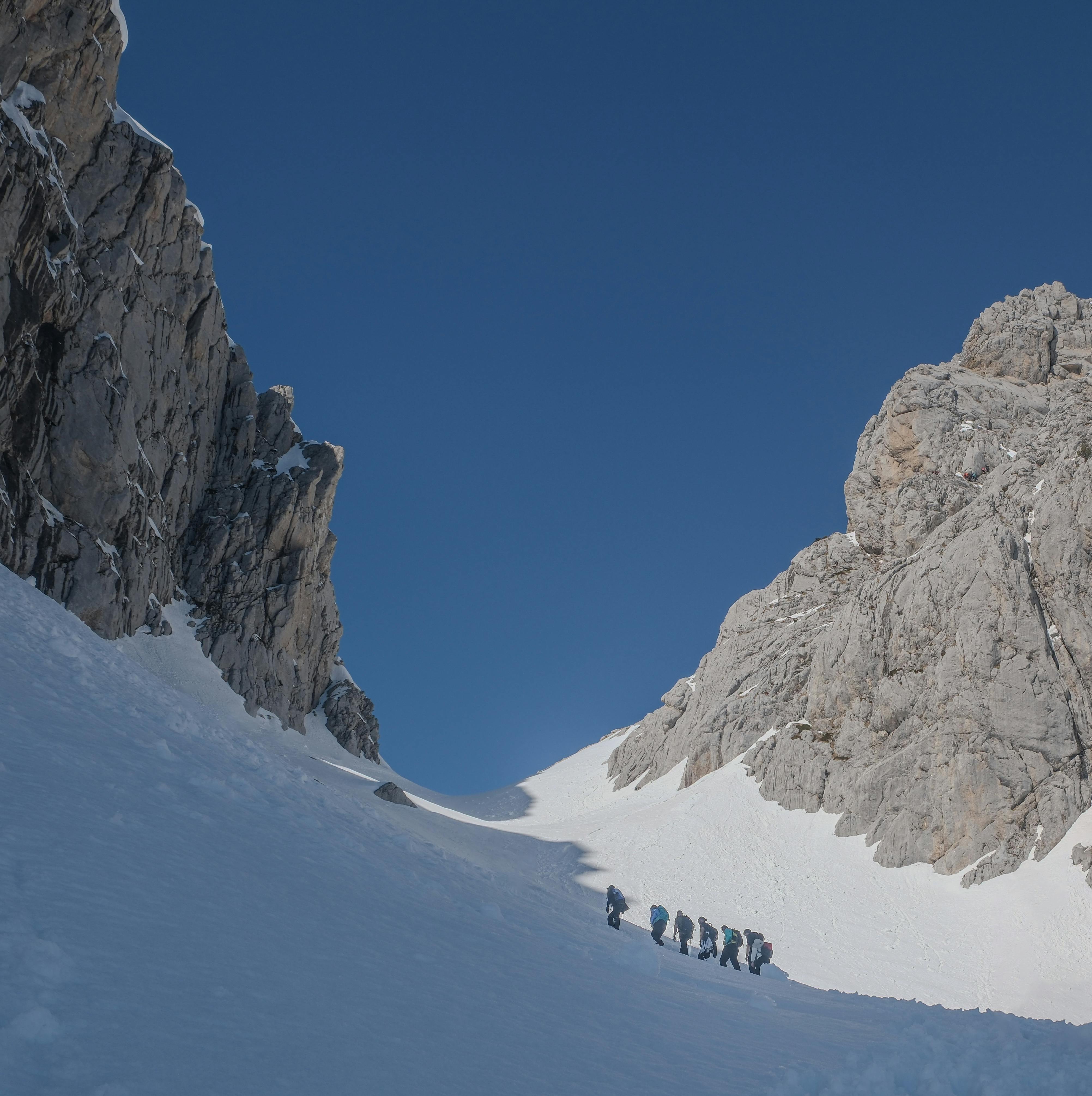Hikers Trekking Through Snowy Mountain Pass · Free Stock Photo