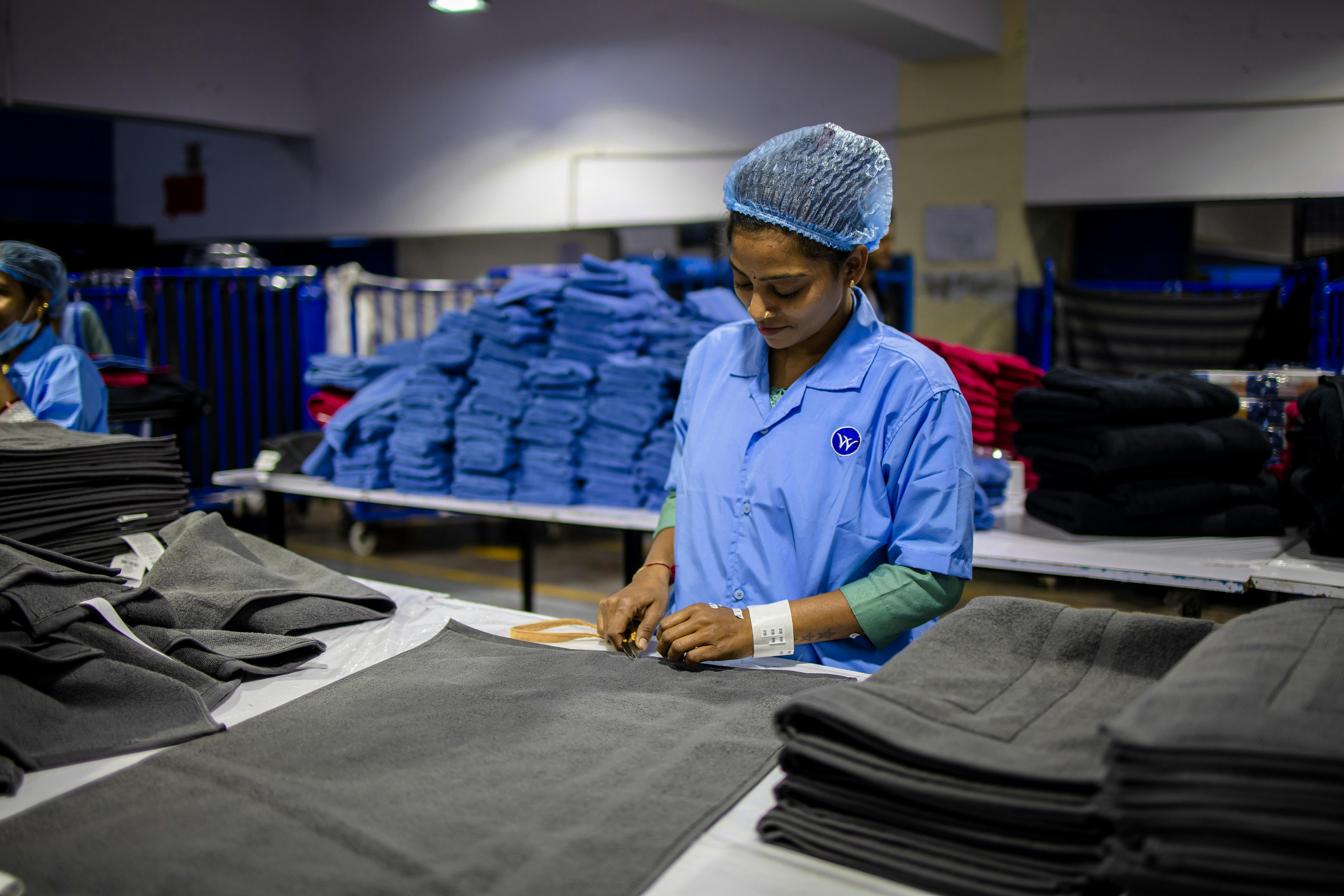 Textile Factory Worker in Blue Uniform Sorting Fabrics · Free Stock Photo