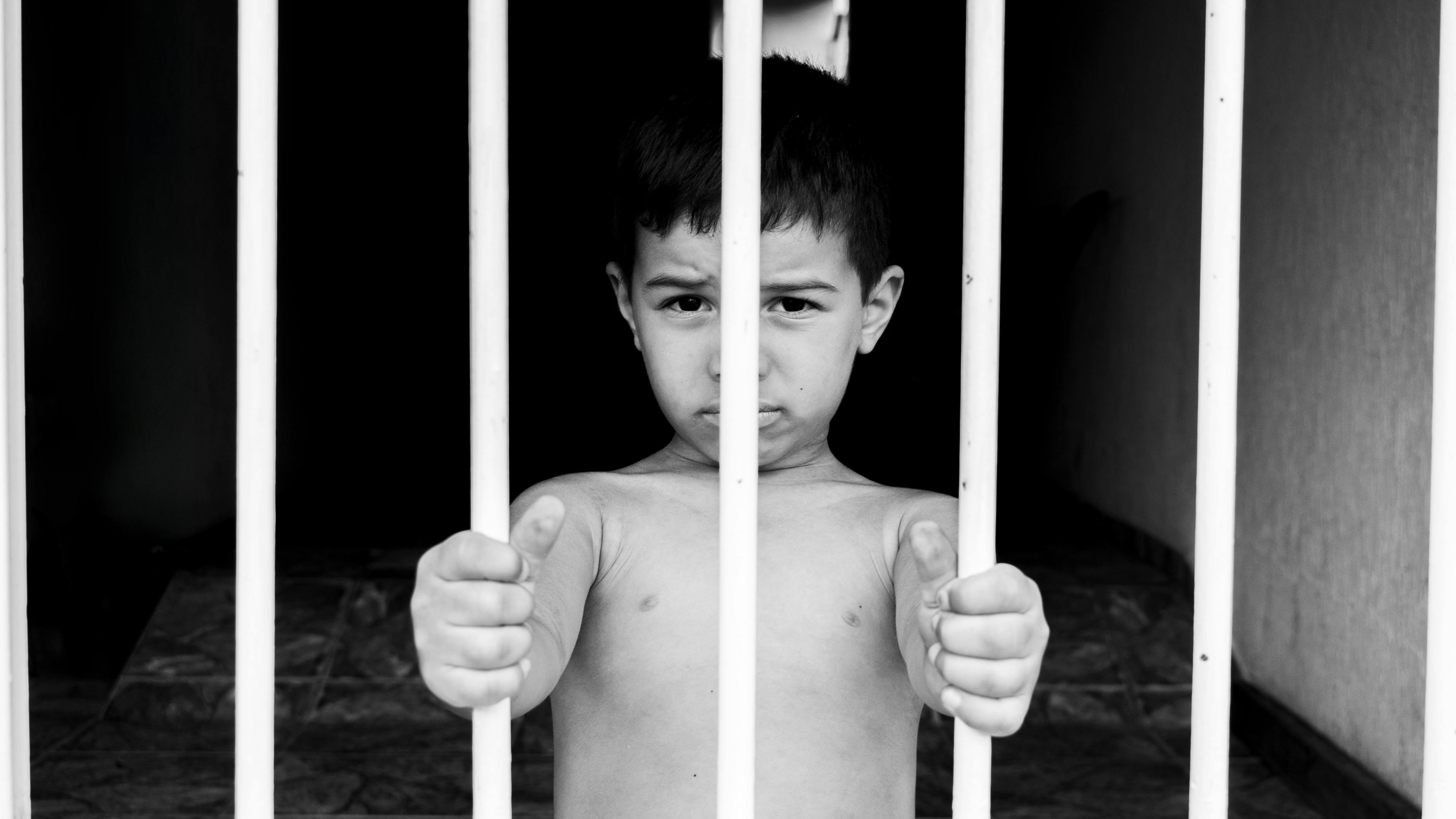Black and White Portrait of a Child Behind Bars · Free Stock Photo
