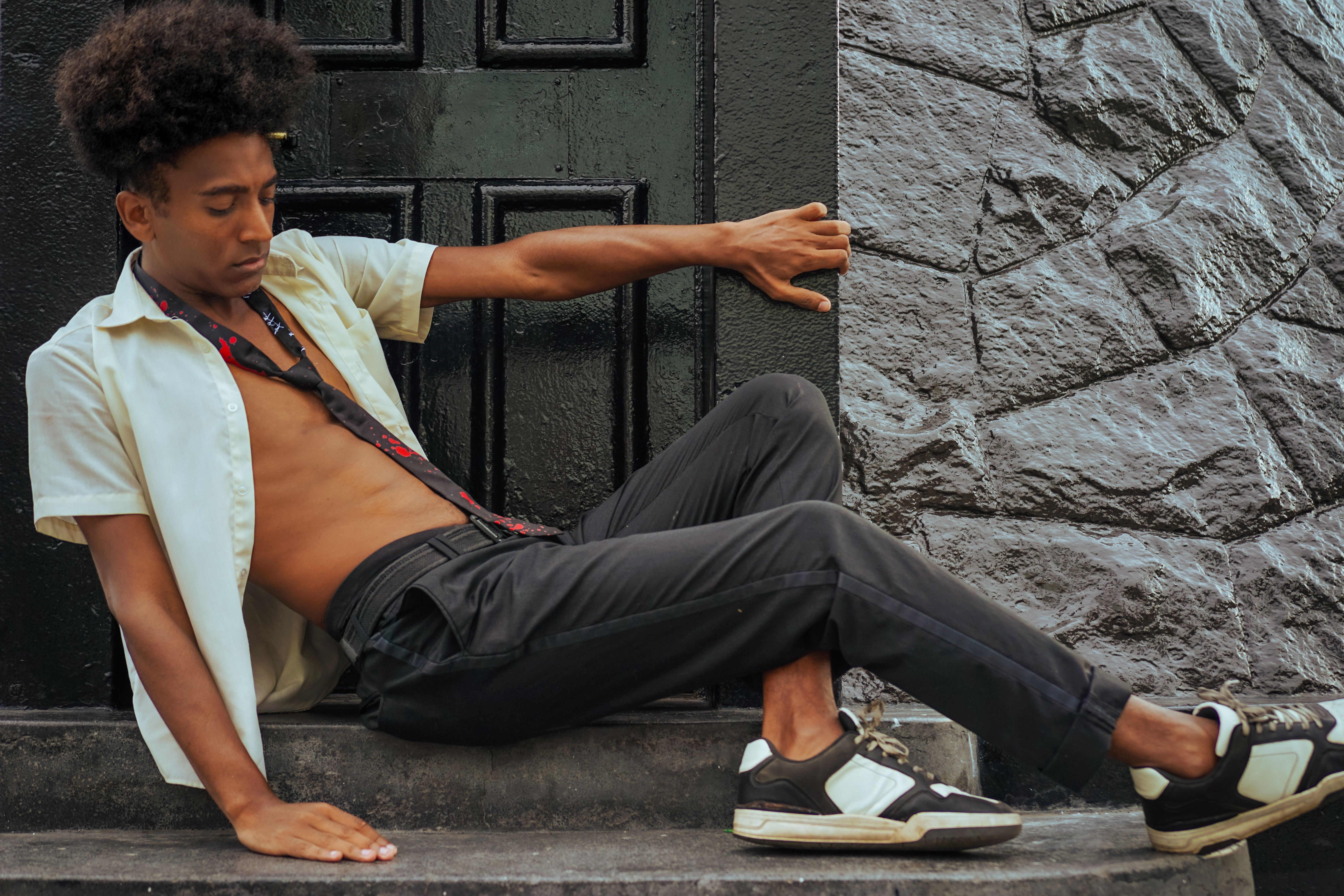 Young Man Resting Against Stone Wall Outdoors · Free Stock Photo