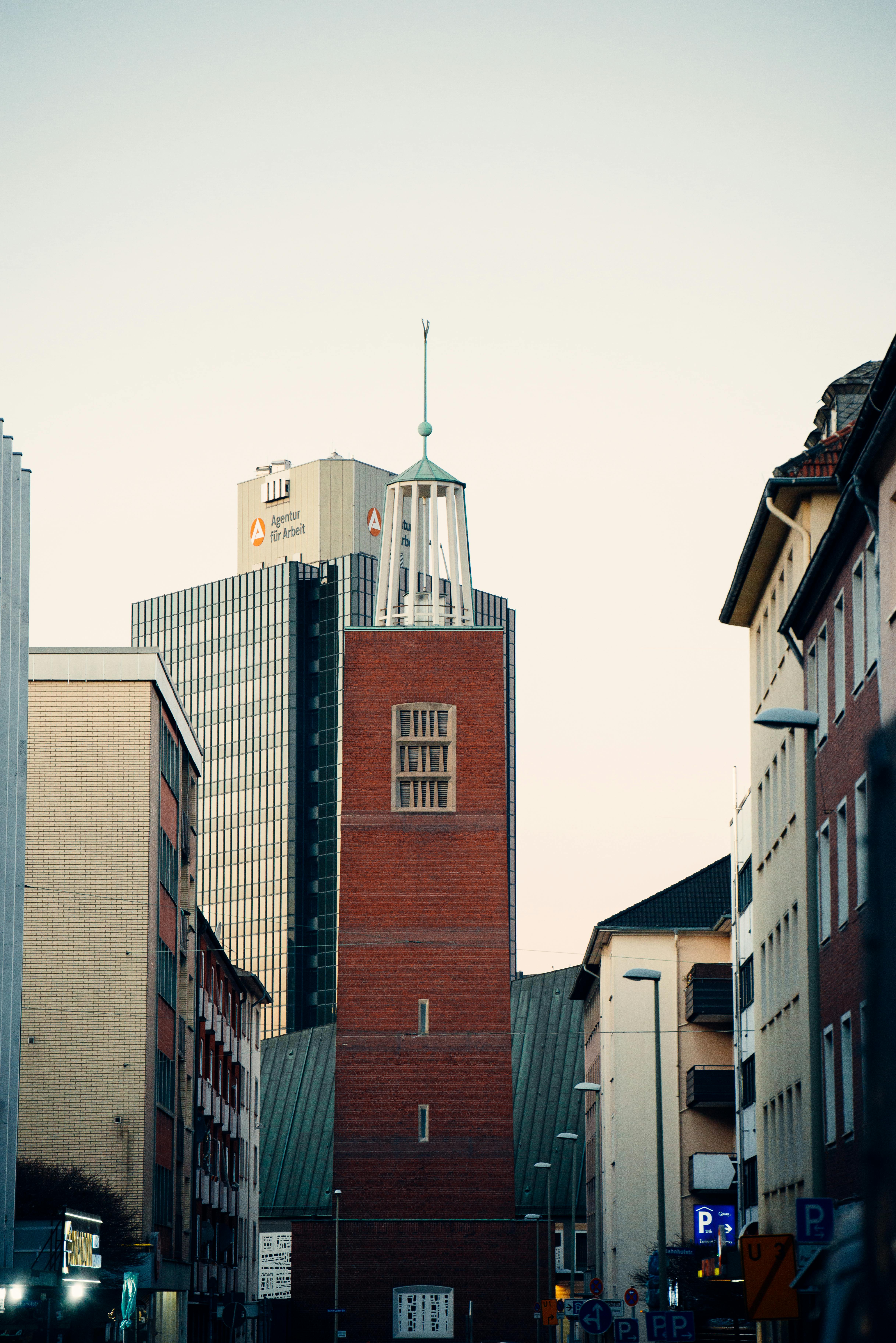 Cityscape Featuring Brick Tower and Modern Skyscraper · Free Stock Photo