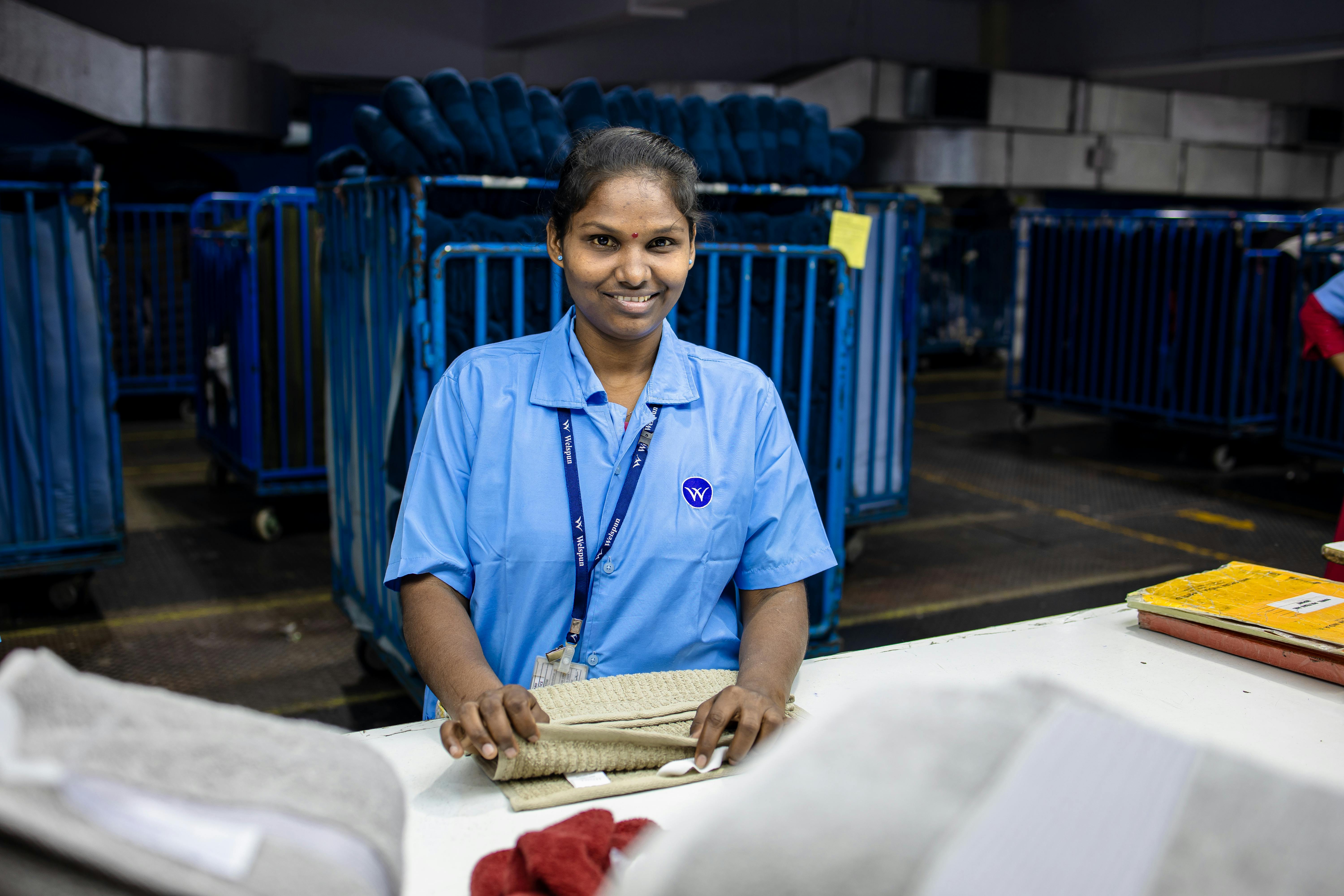 Smiling Factory Worker Folding Textiles in Warehouse · Free Stock Photo
