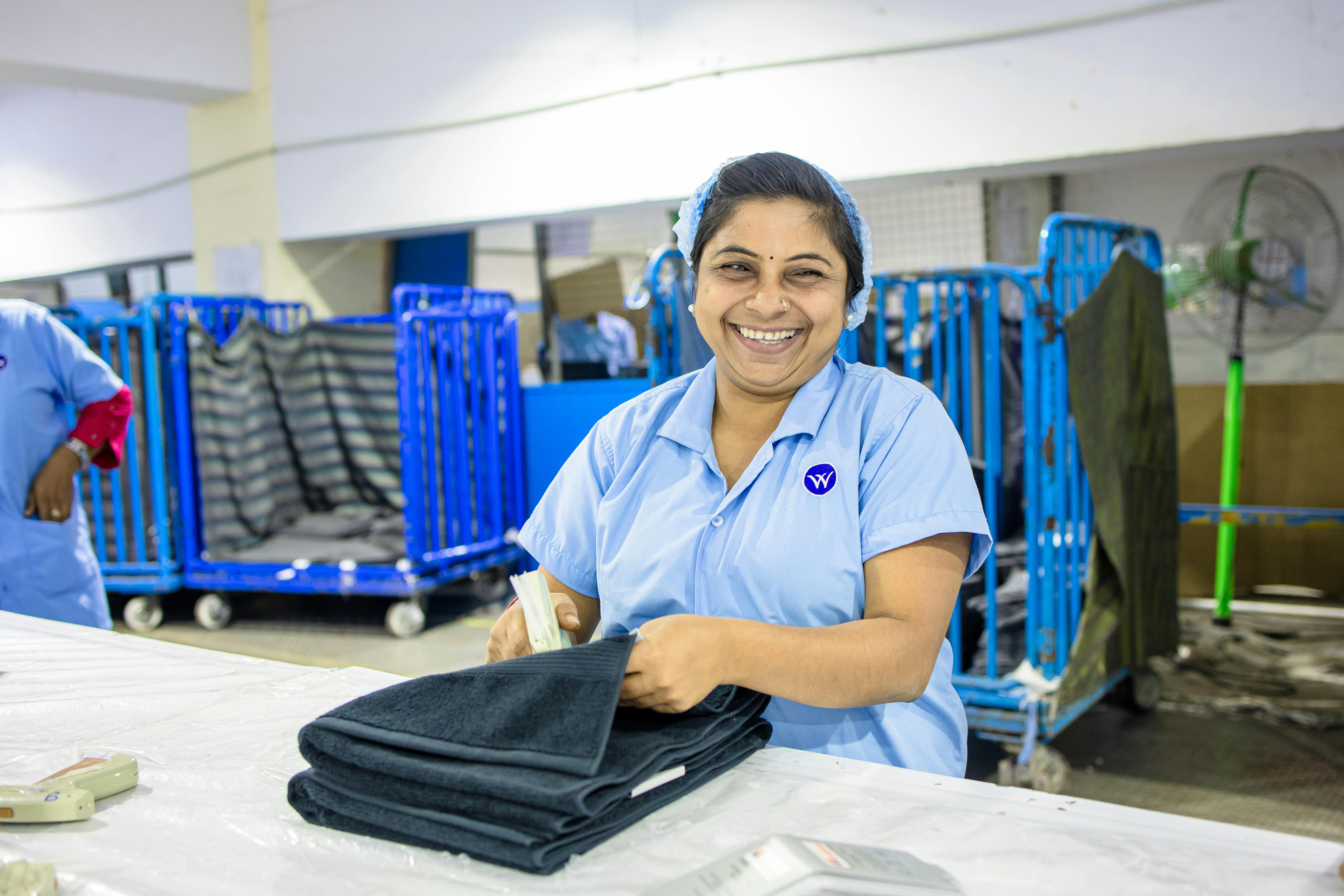 Smiling Textile Worker Folding Clothes in Factory · Free Stock Photo