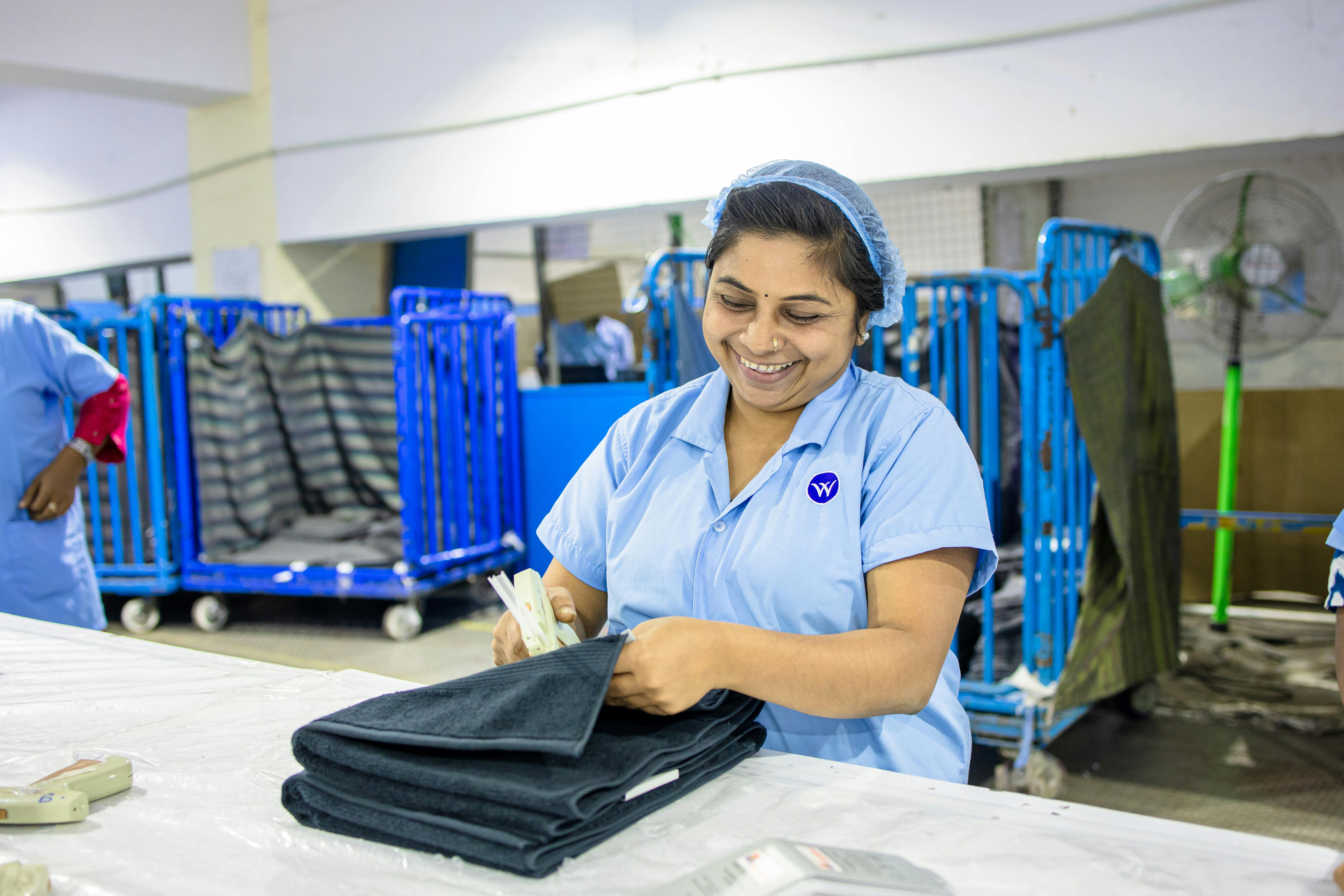 Smiling Textile Worker Sorting in Factory Setting · Free Stock Photo