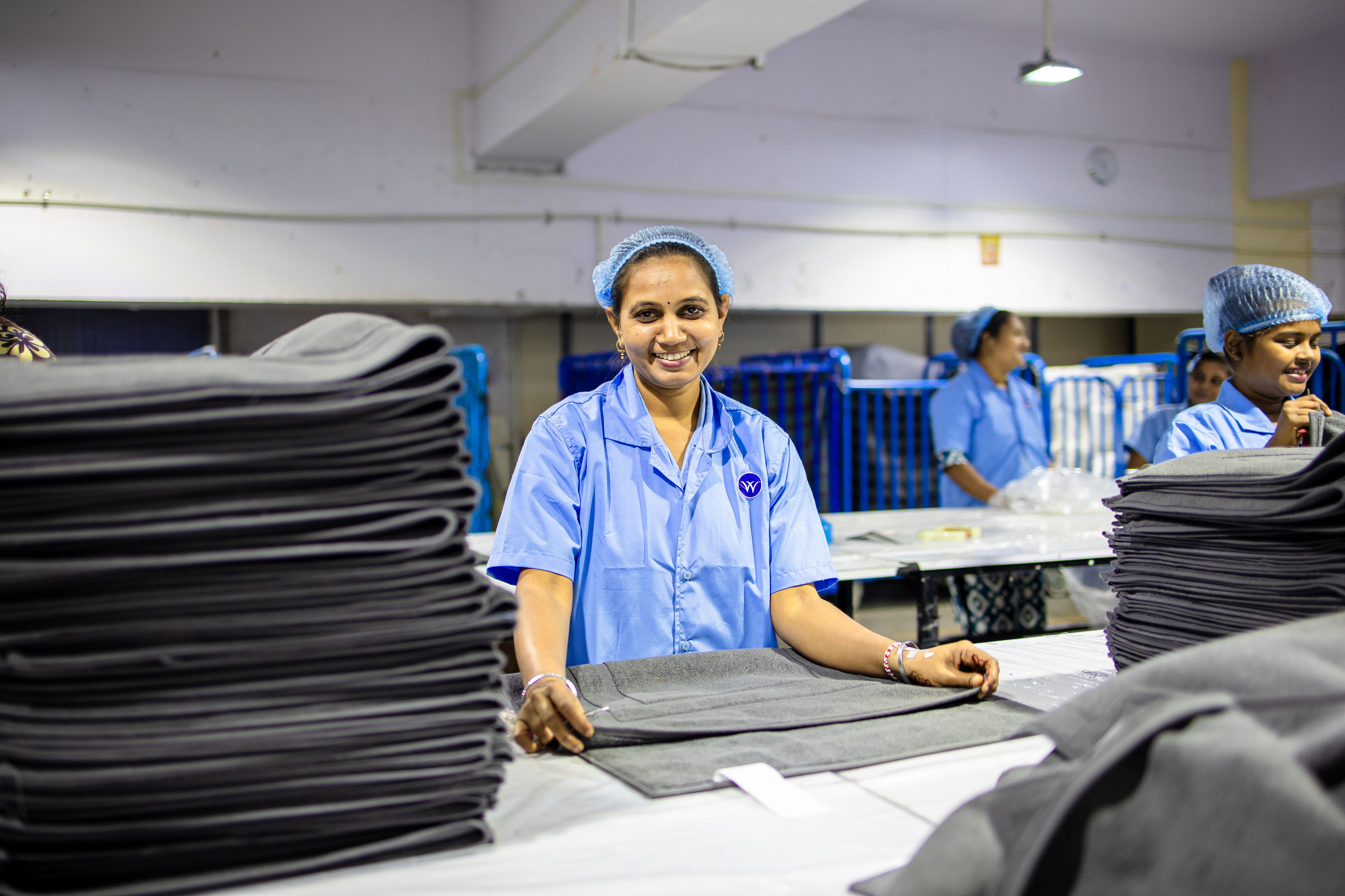 Smiling Factory Workers Folding Textiles Indoors · Free Stock Photo