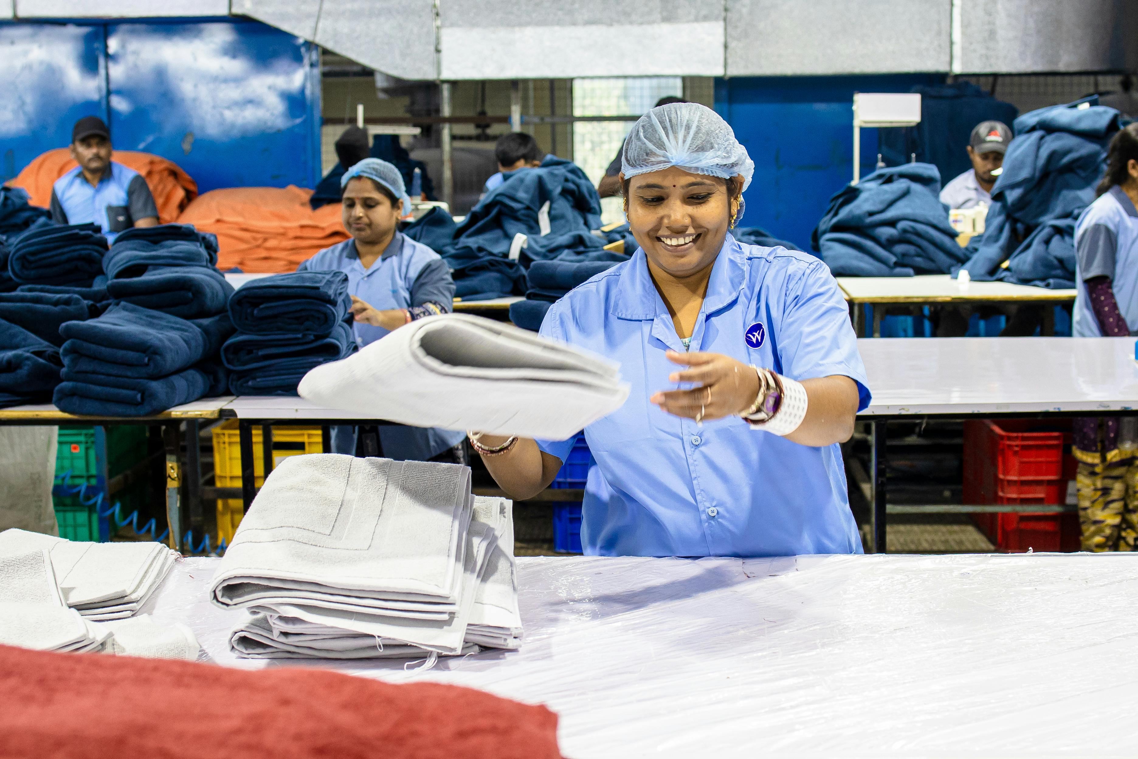 Smiling Workers in Textile Factory Folding Fabric · Free Stock Photo