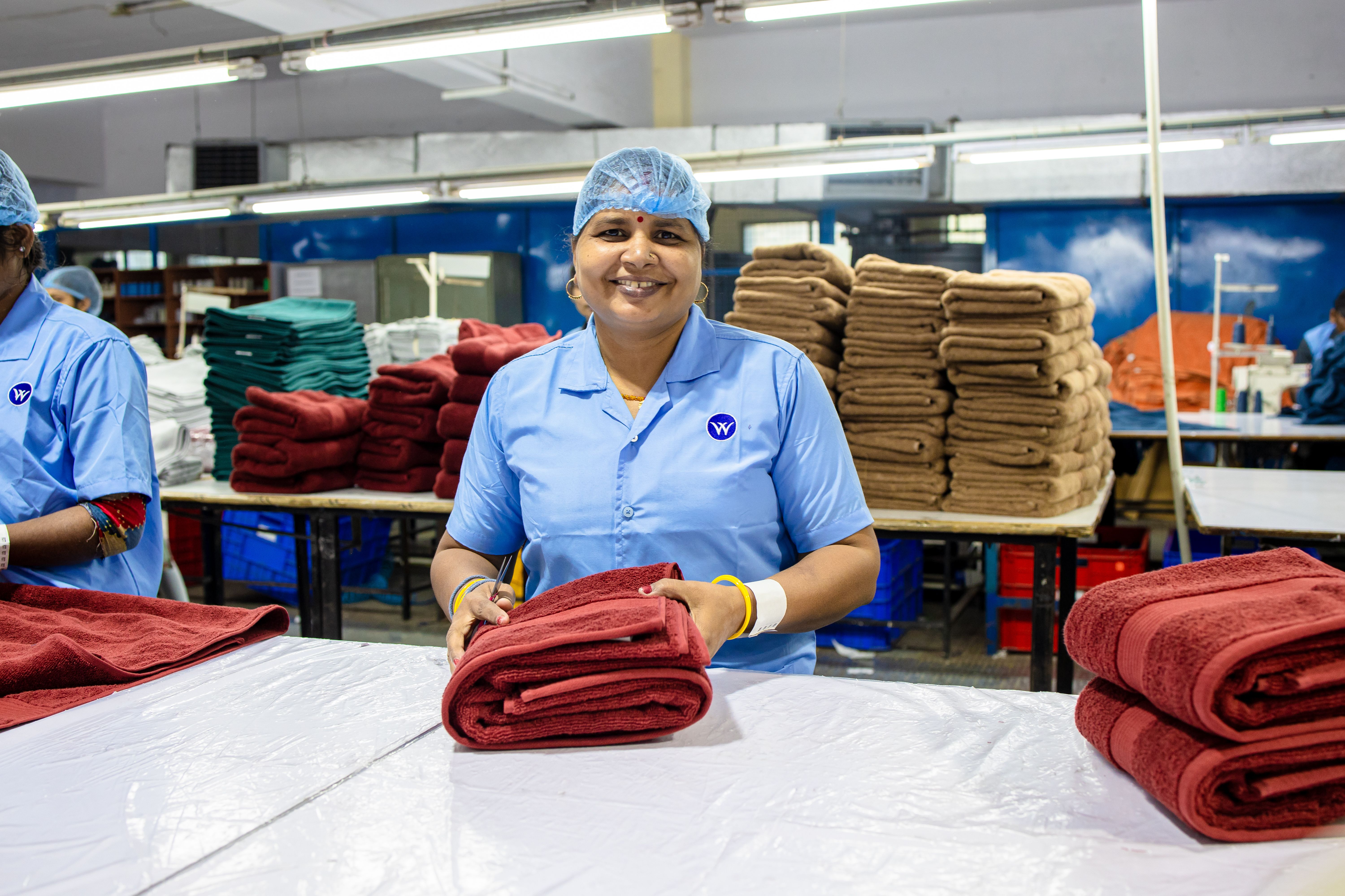 Smiling Textile Worker Sorting Towels in Factory · Free Stock Photo