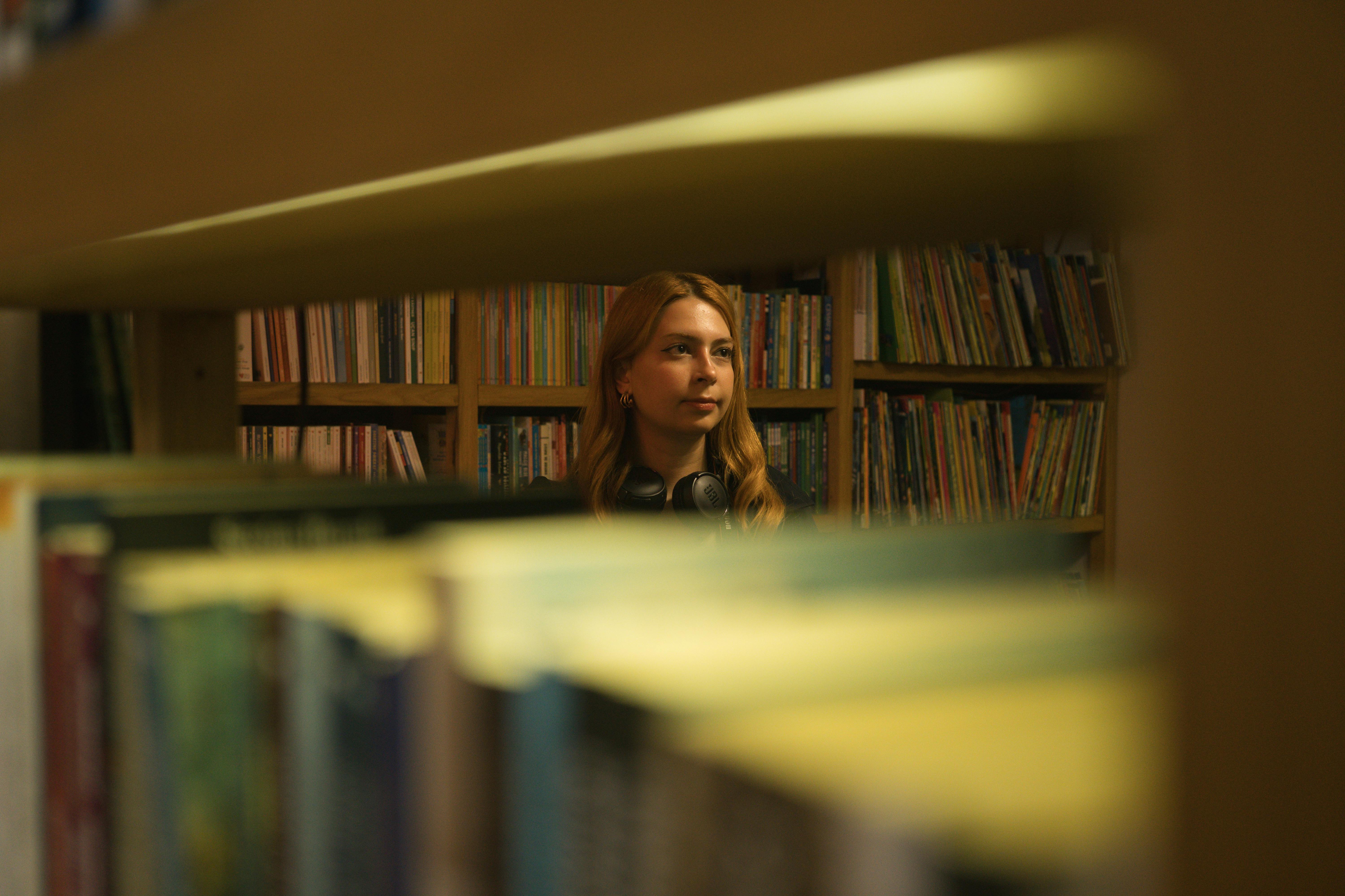 Young Woman Browsing Library Bookshelves · Free Stock Photo