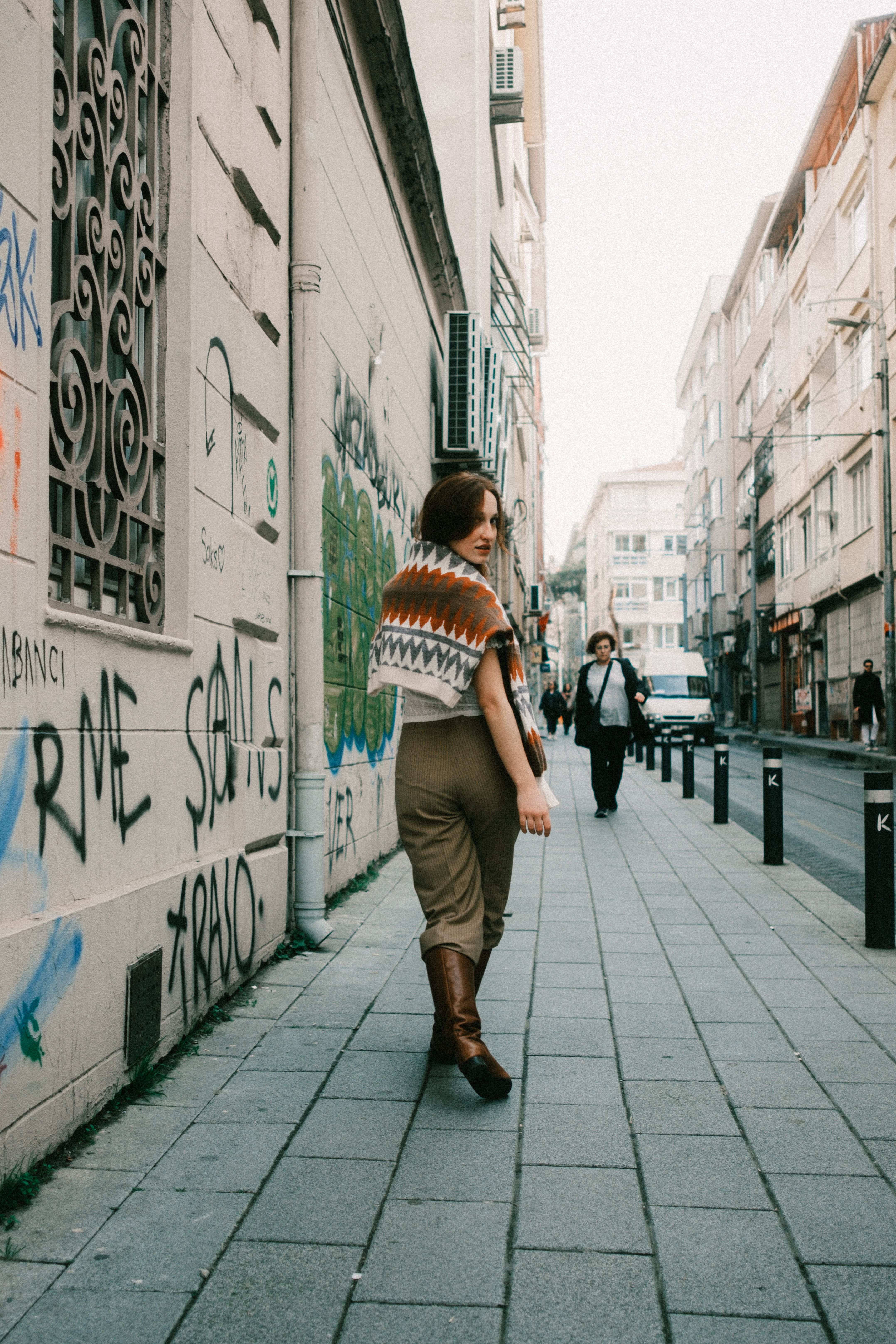 Woman Walking on Graffiti-Lined Urban Sidewalk · Free Stock Photo
