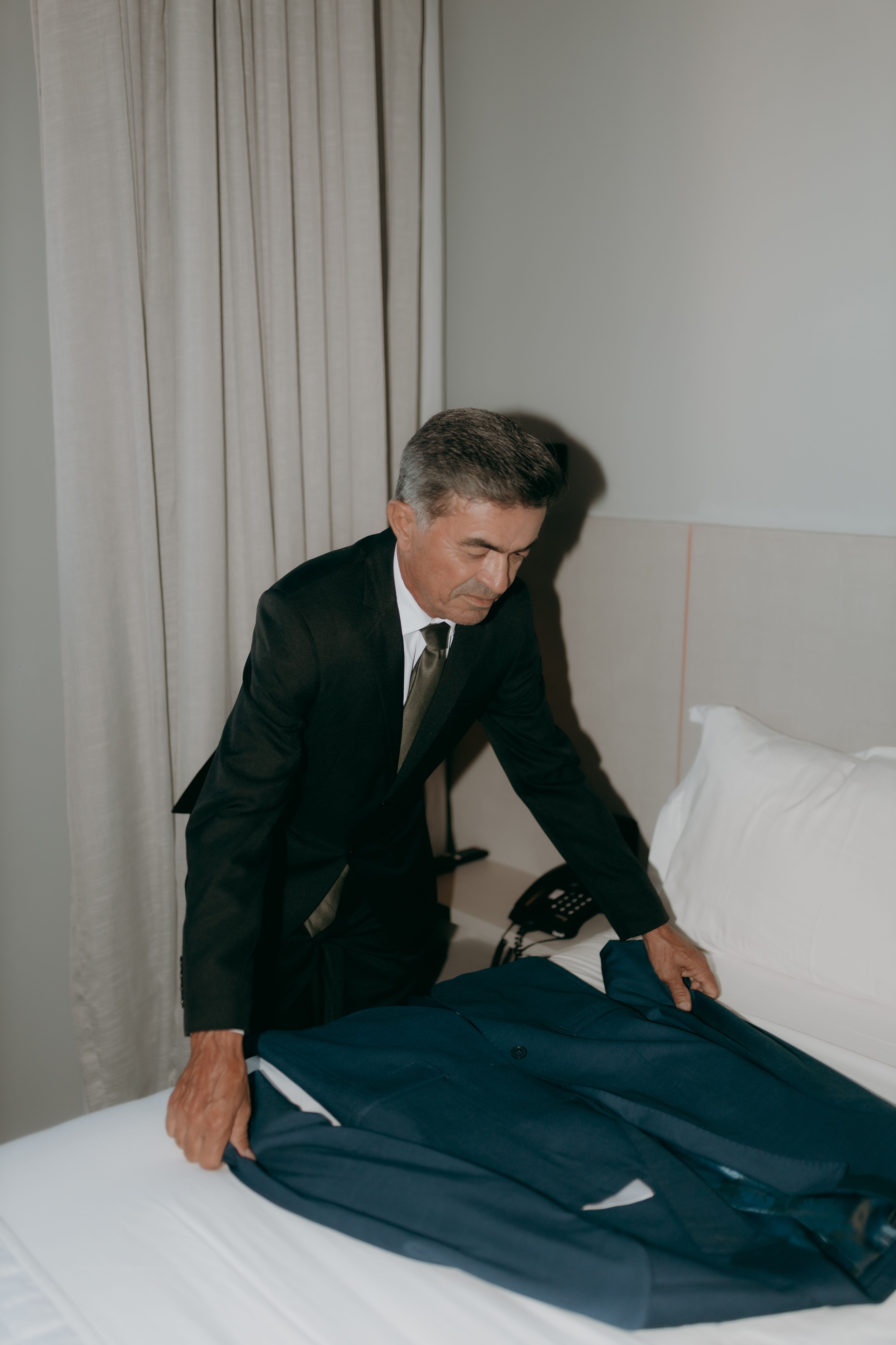 Man in Suit Preparing Clothes in Hotel Room · Free Stock Photo