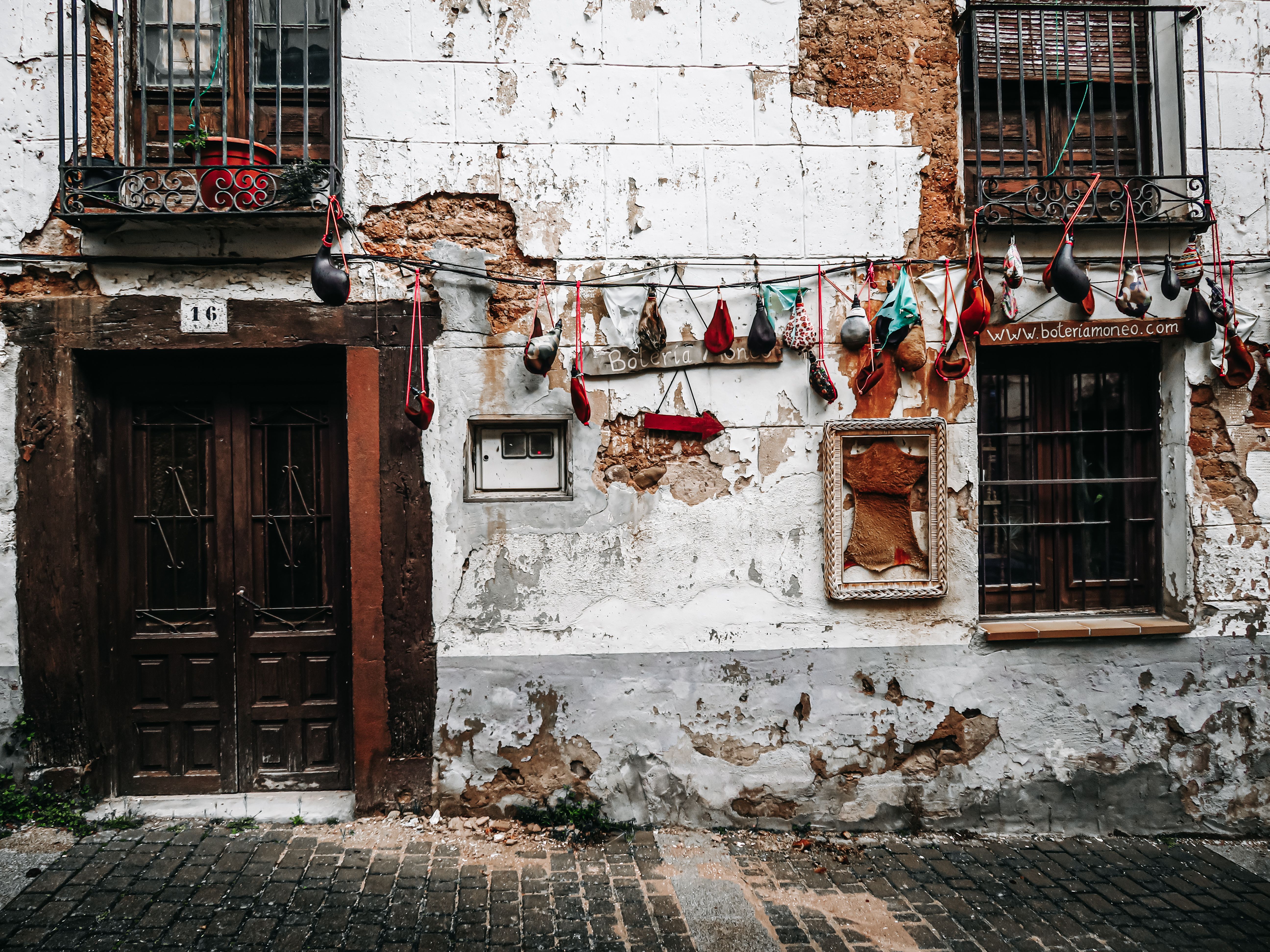 Rustic Spanish Street Wall with Hanging Wineskins · Free Stock Photo