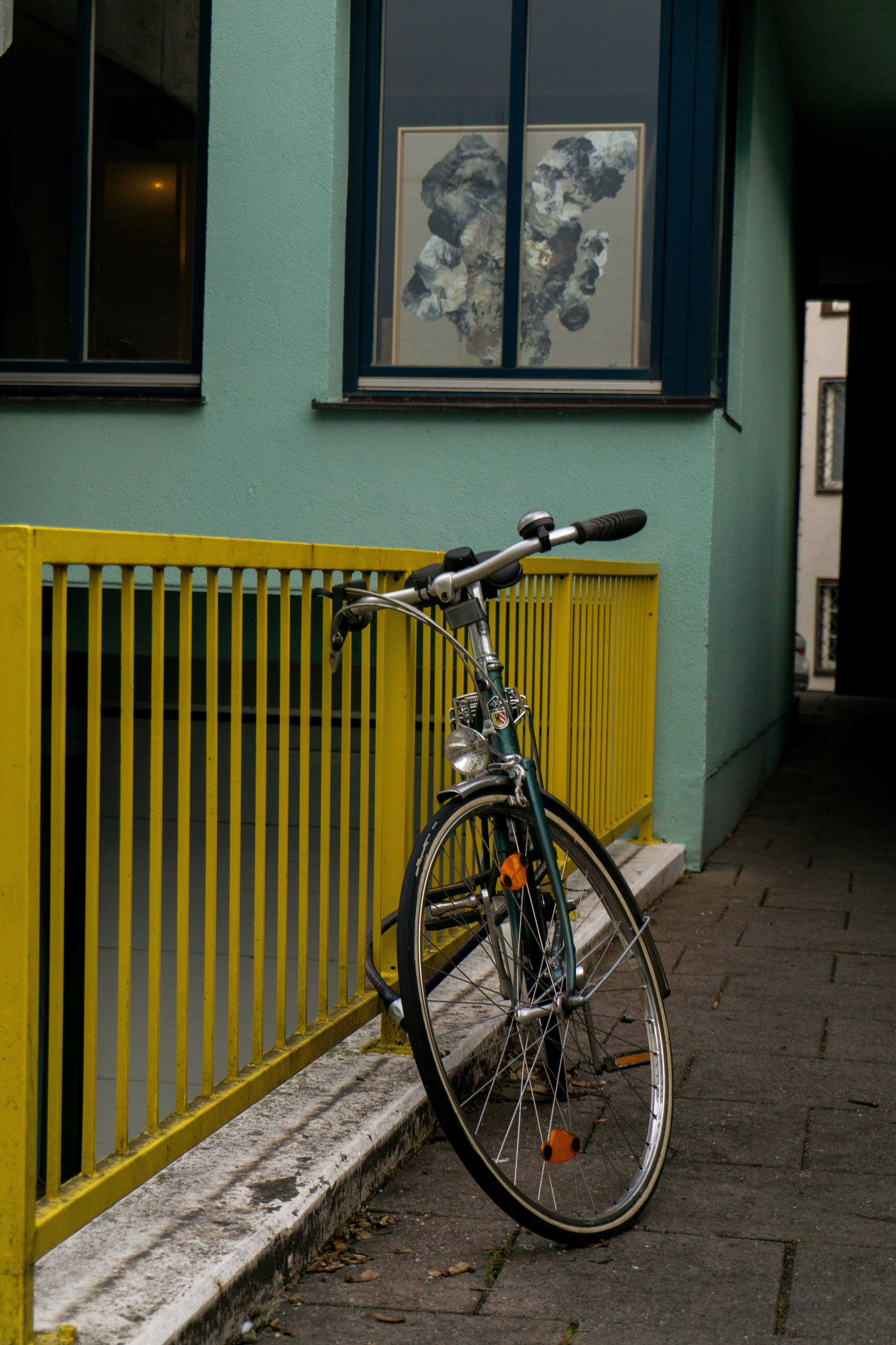 Urban Bicycle Resting Against Yellow Railings · Free Stock Photo