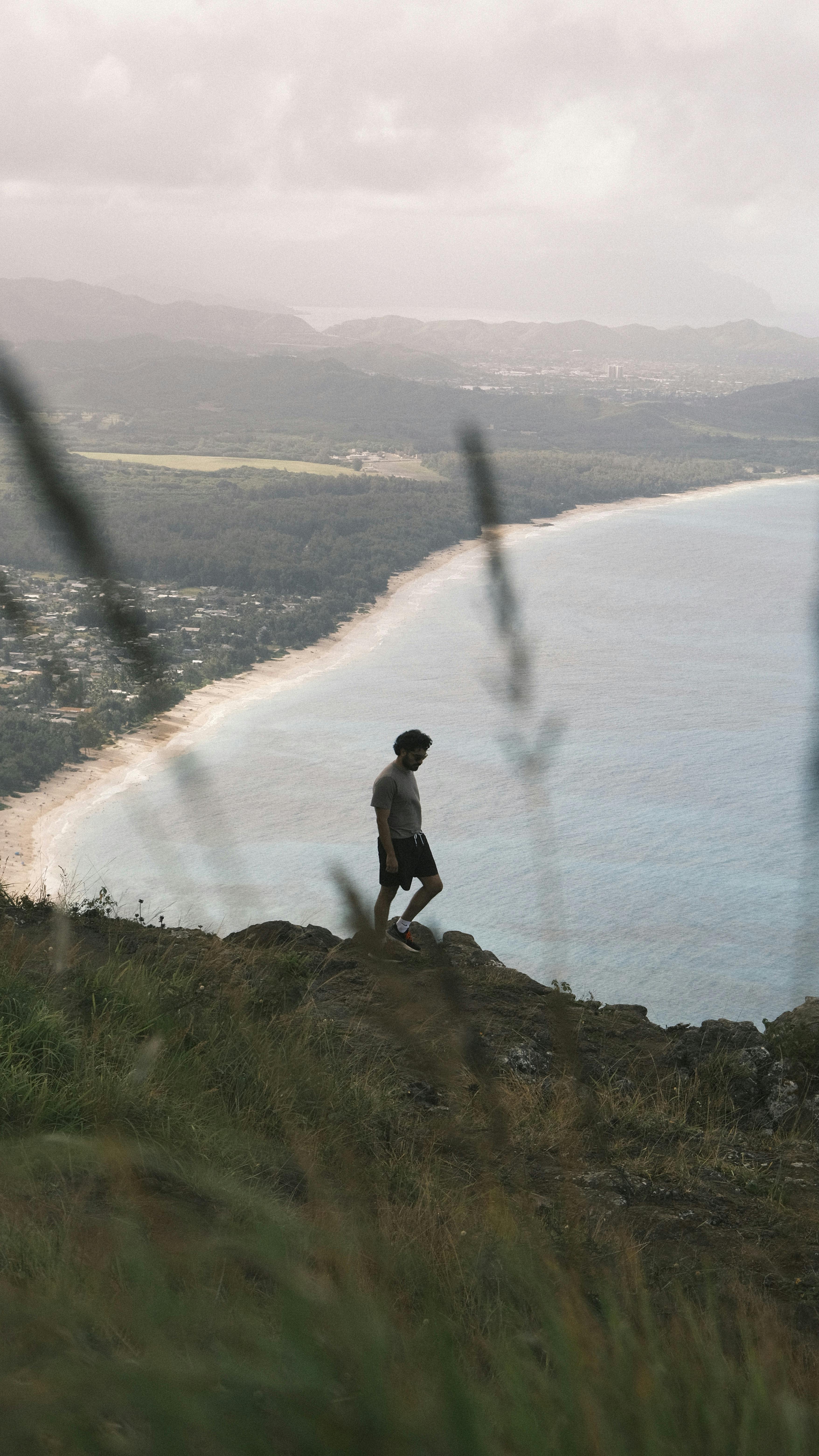 Man Stands on Cliff Overlooking Scenic Coastline · Free Stock Photo