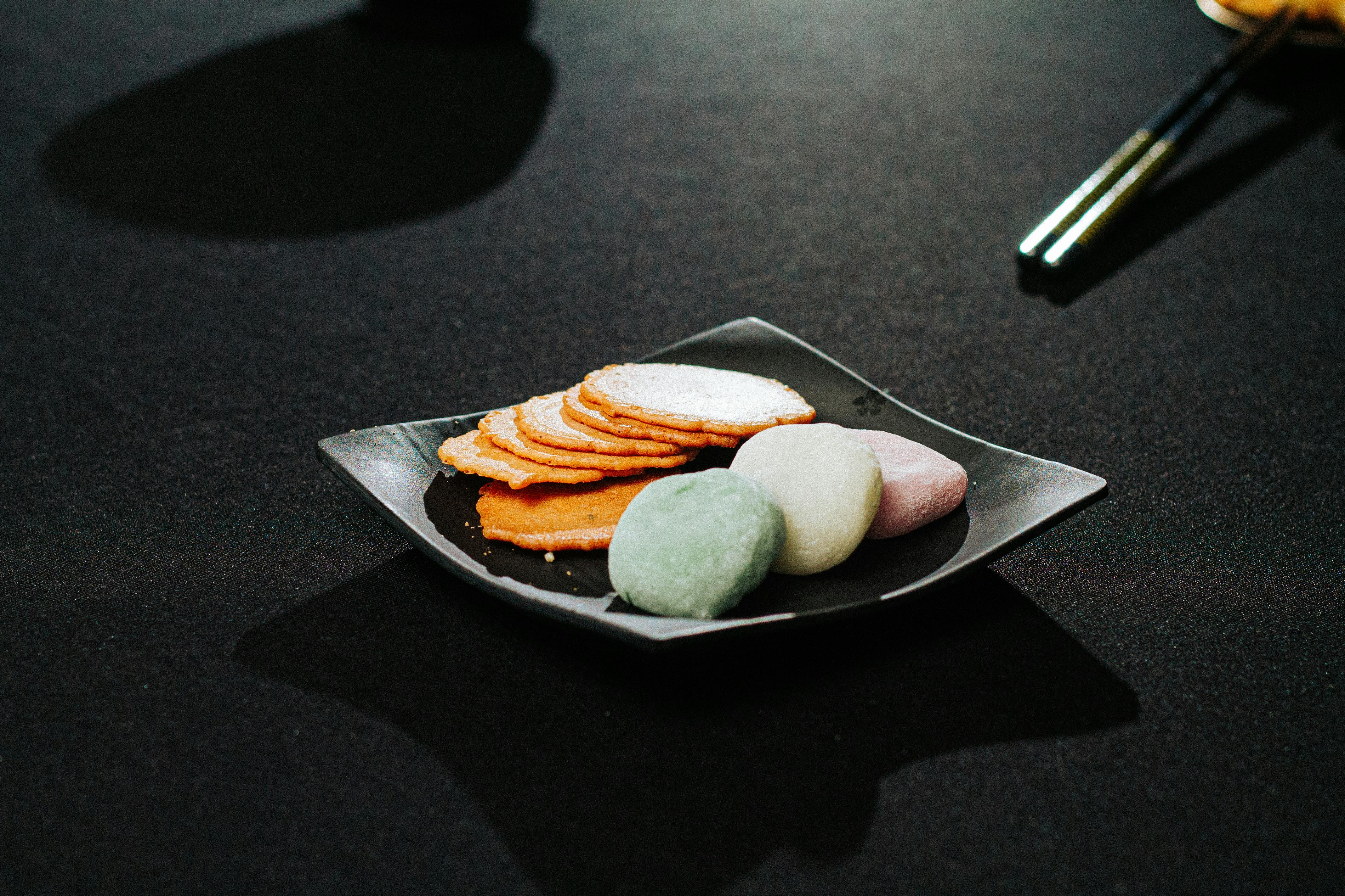Assorted Mochi and Rice Crackers on Black Plate · Free Stock Photo