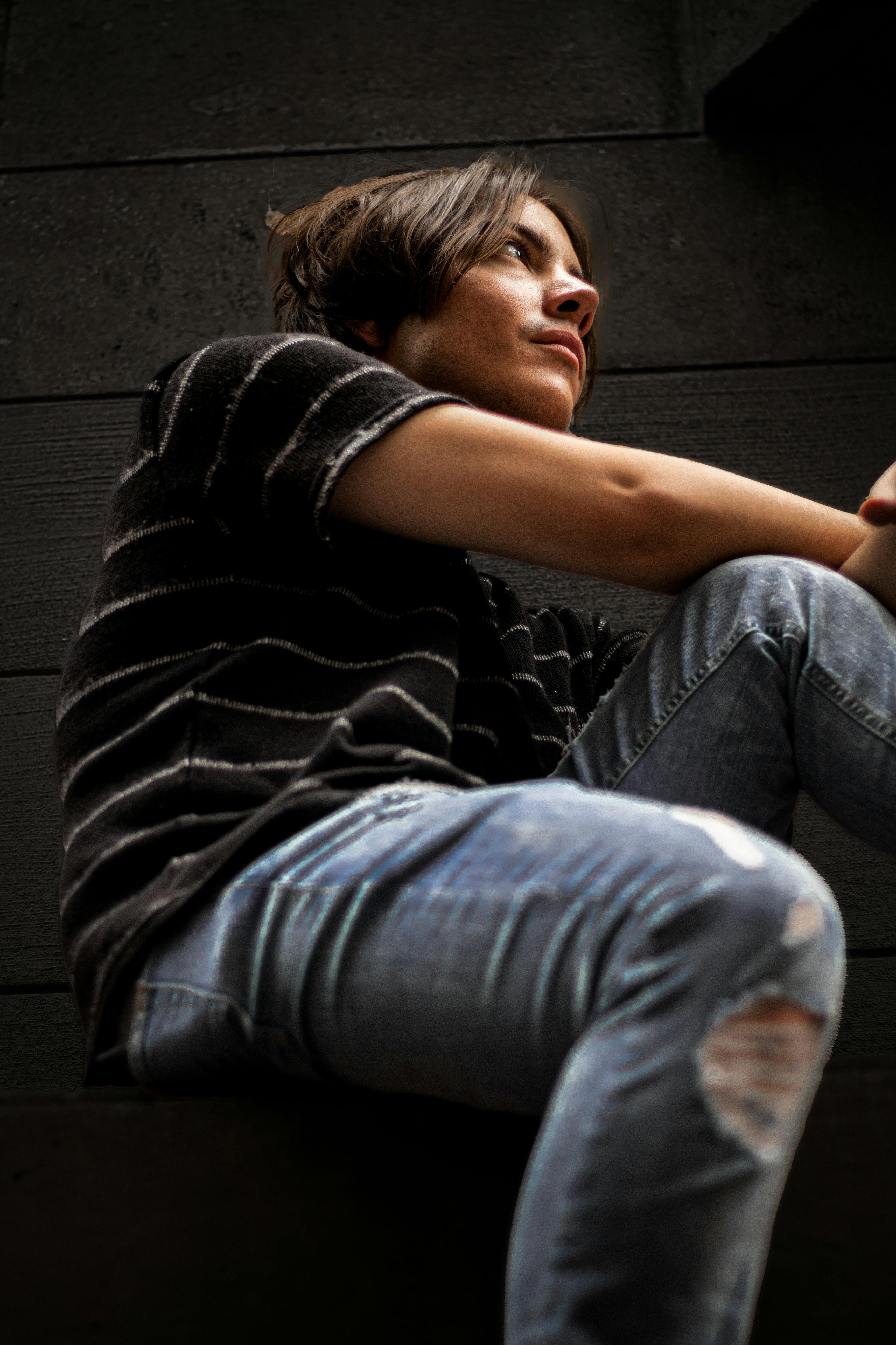 Contemplative Young Man Sitting Against a Wall · Free Stock Photo