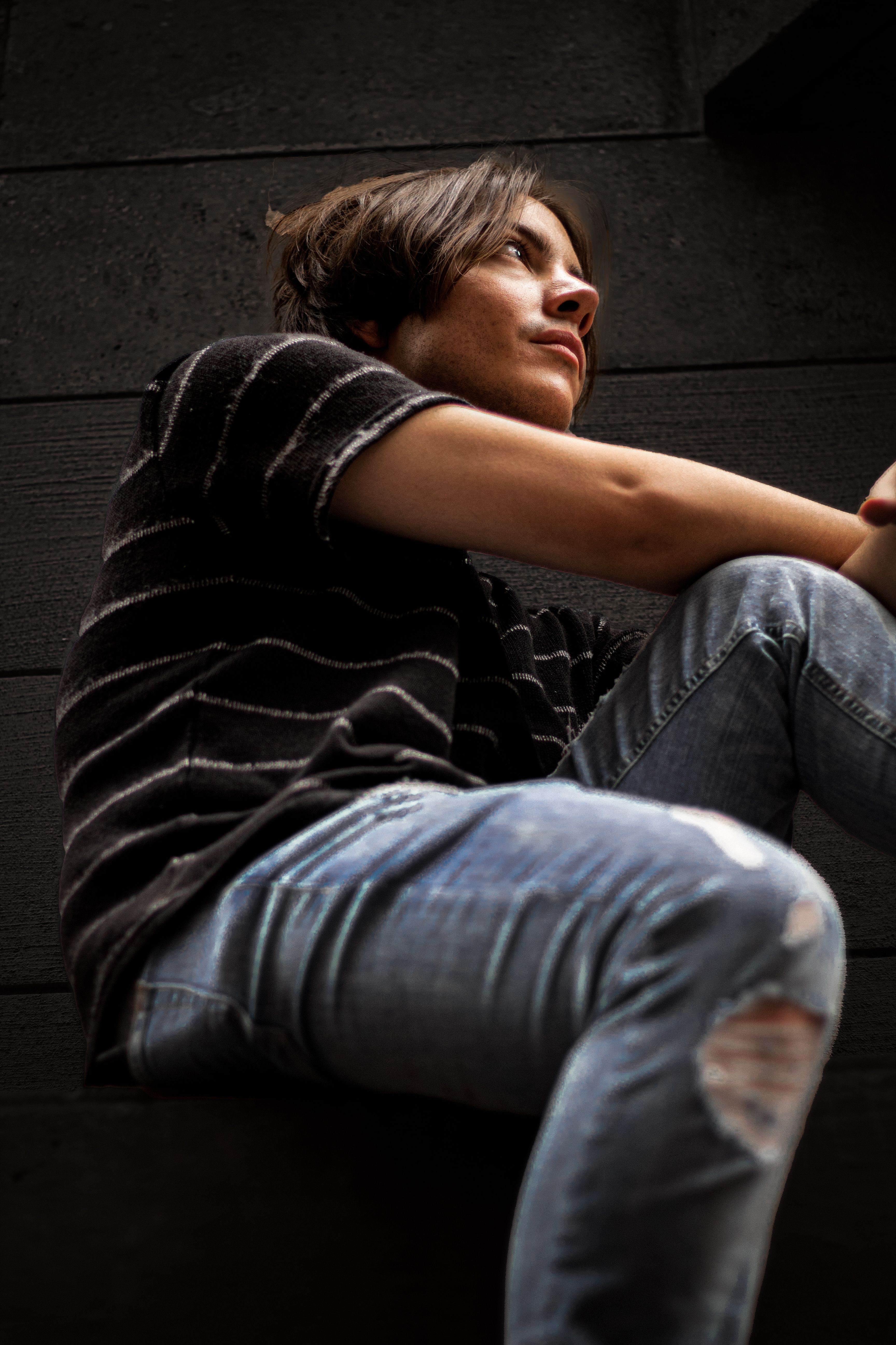 Contemplative Young Man Sitting Against a Wall · Free Stock Photo