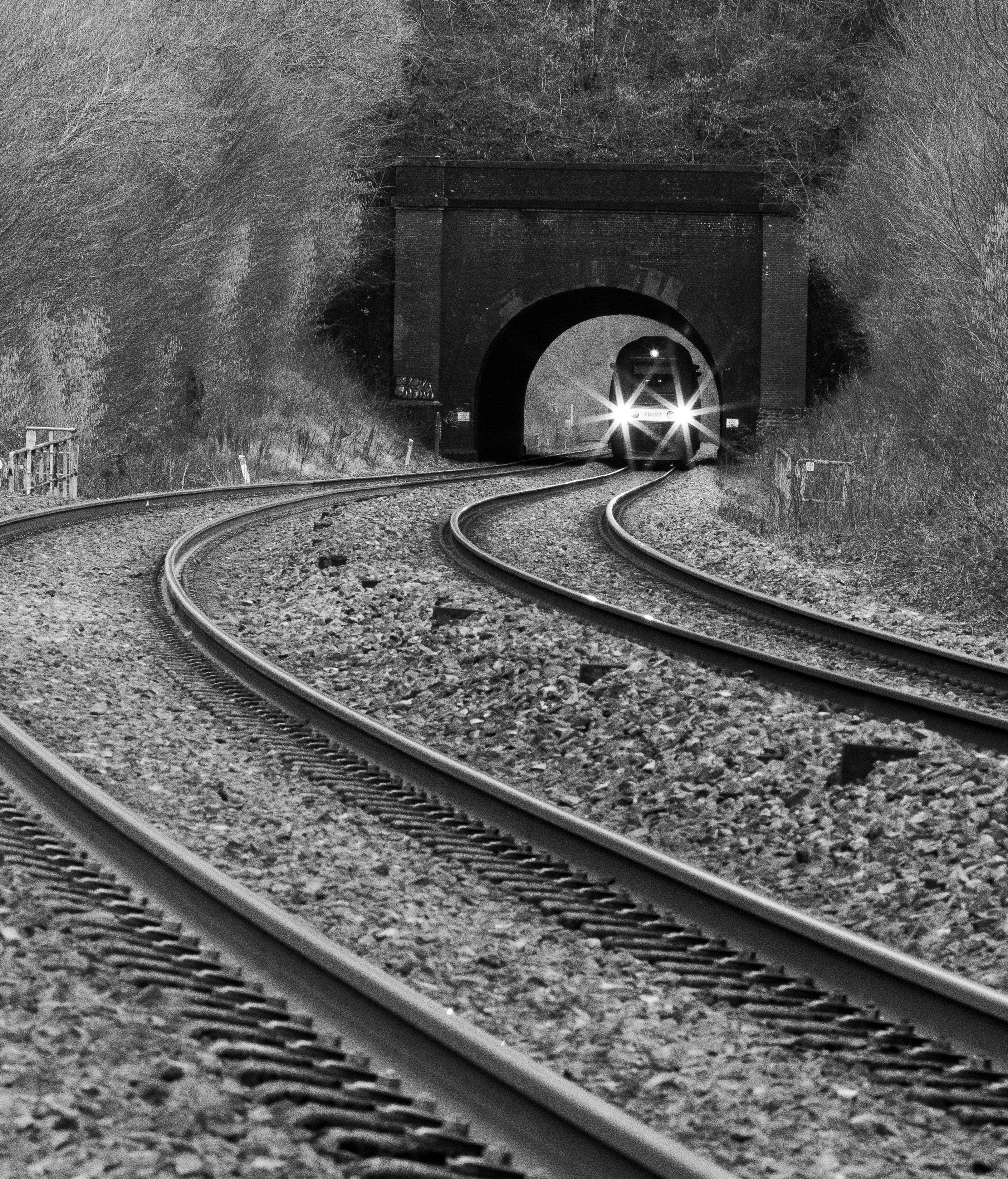 Black and White Train Exiting Tunnel on Curved Tracks · Free Stock Photo