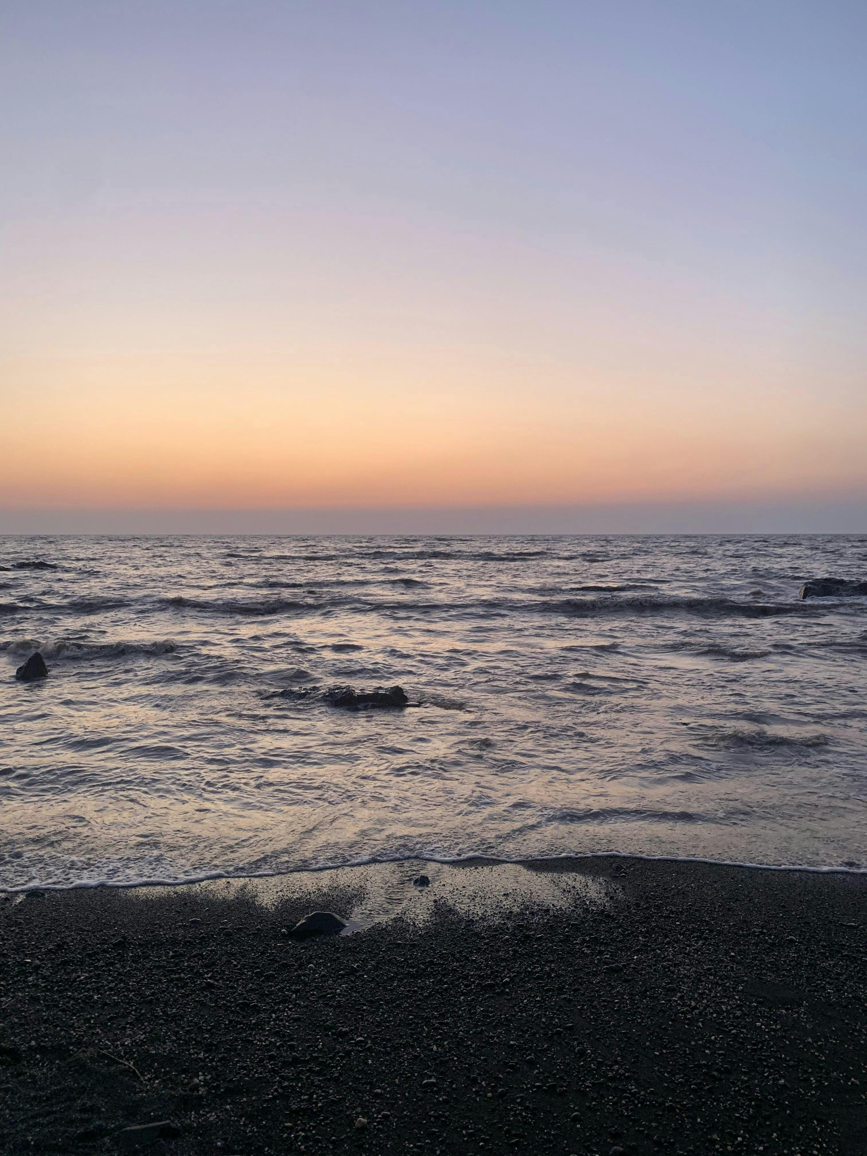 Serene Ocean Sunset with Waves Hitting Shore · Free Stock Photo