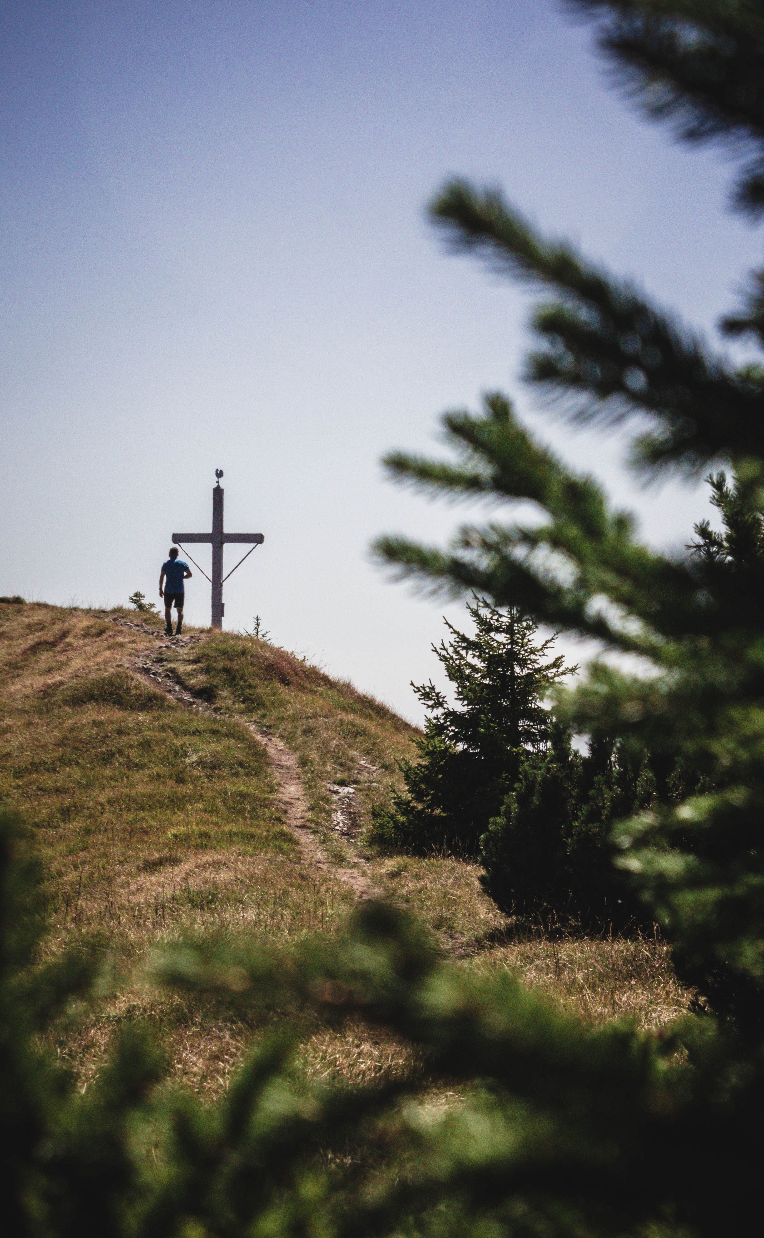 Hiker Approaching Cross on Hilltop Trail · Free Stock Photo